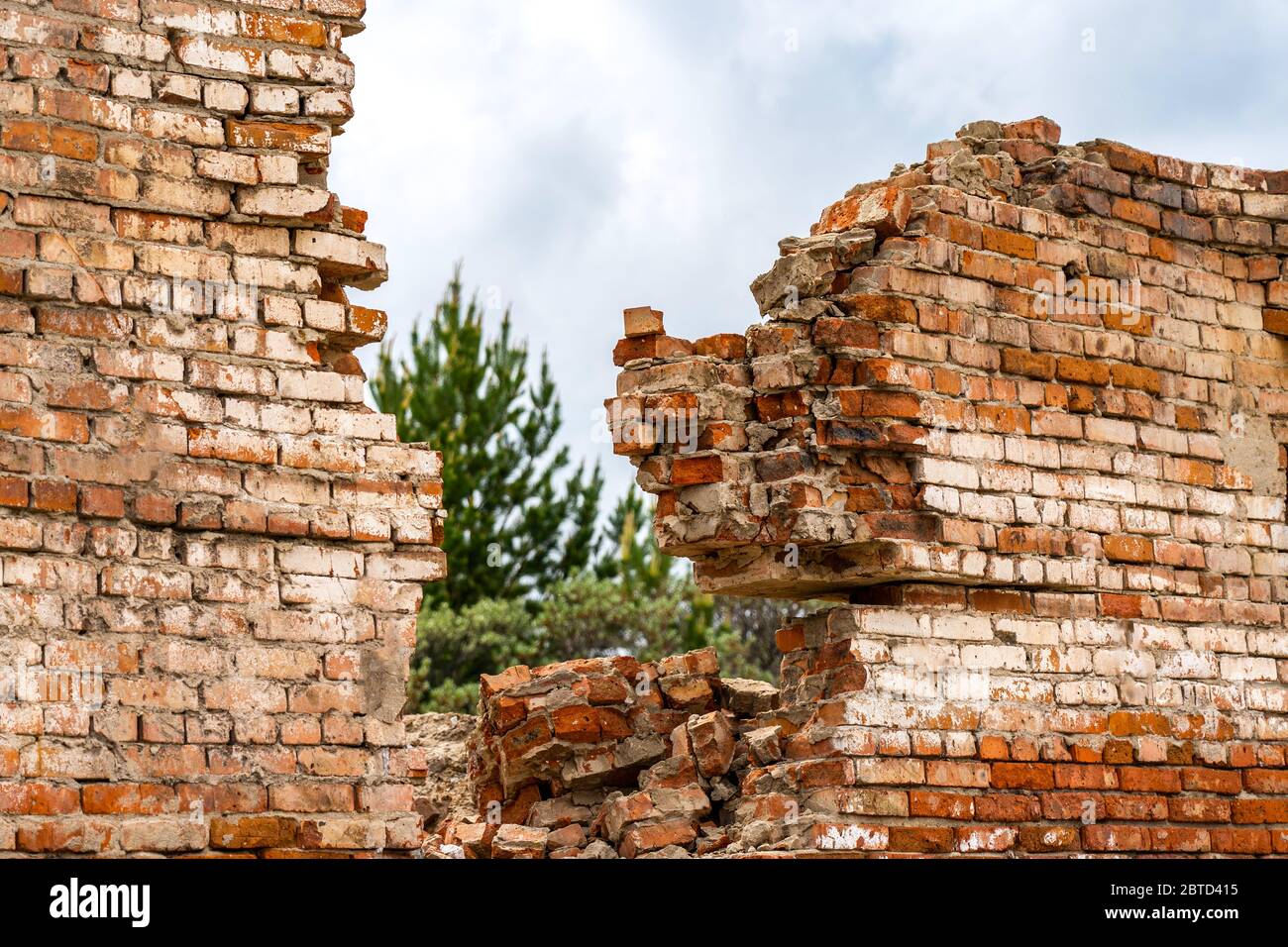 Rift in a brick wall. Close-up. Ruined red brick wall. The wreckage of the wall against the sky ...