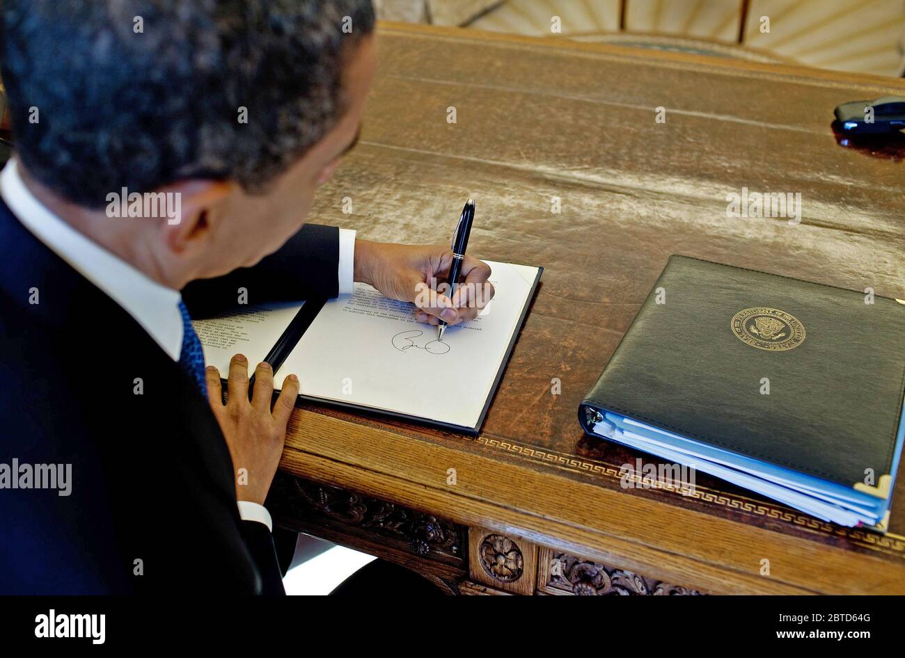 President Barack Obama writes at his desk in the Oval Office 3/3/09 ...