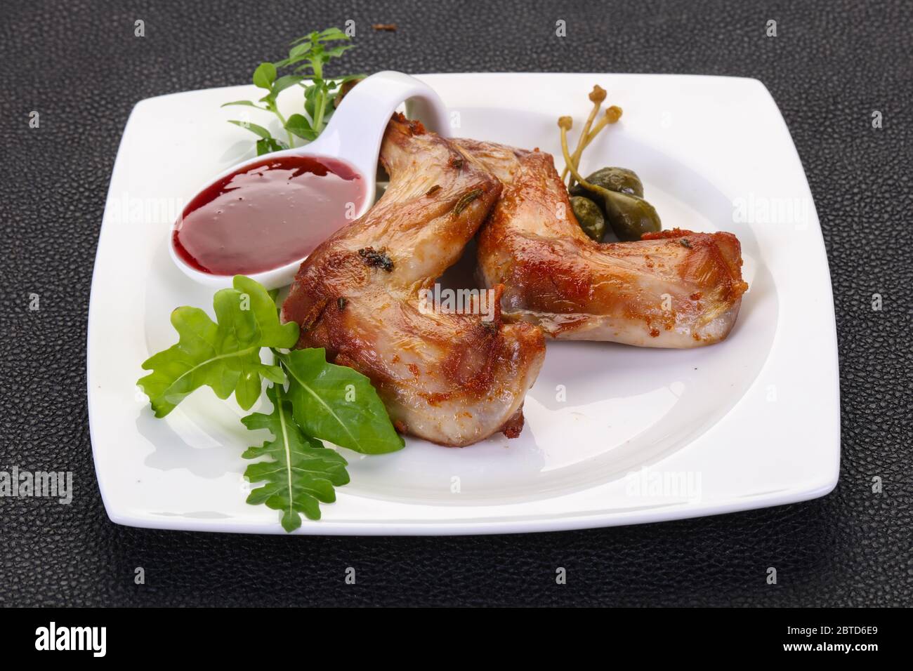 Roasted rabbit legs with cowberry sauce Stock Photo - Alamy
