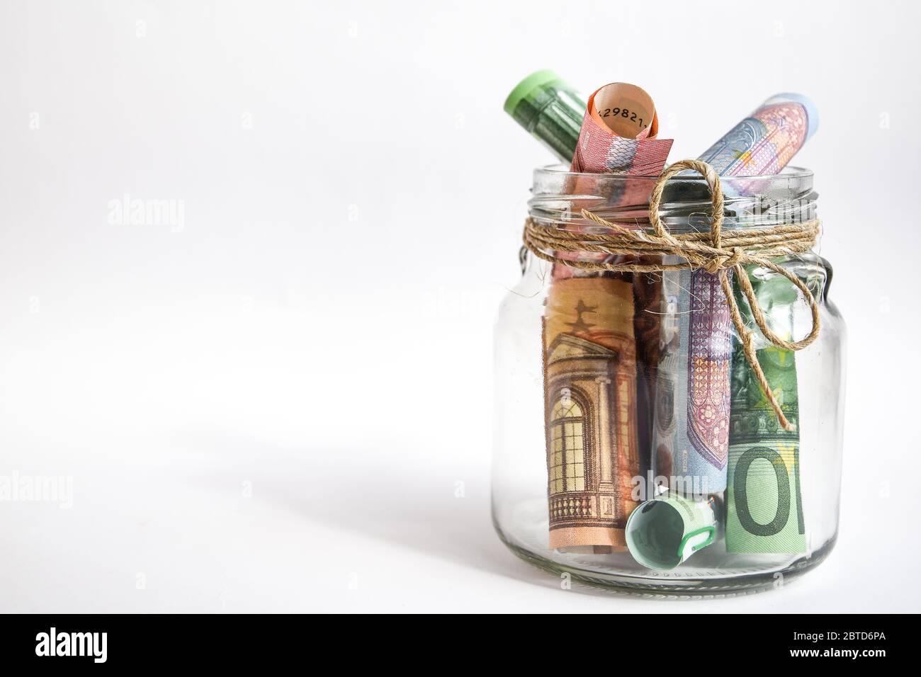 Glass jar with euro notes isolated on white background, euros rolled up ...