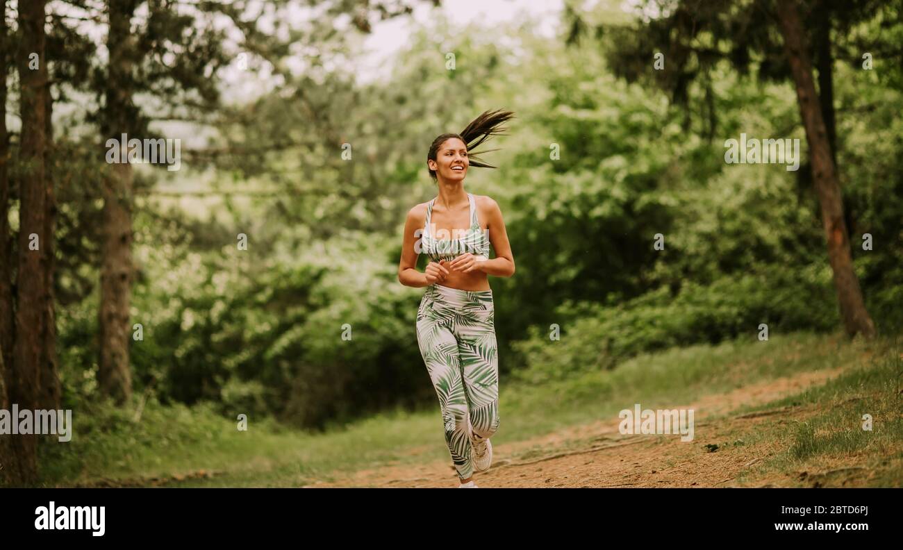 Pretty young fitness woman running at the forest trail Stock Photo - Alamy