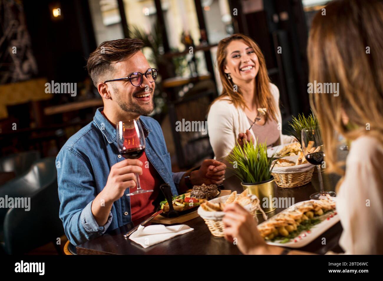 Group of happy young people having dinner in the restaurant Stock Photo ...