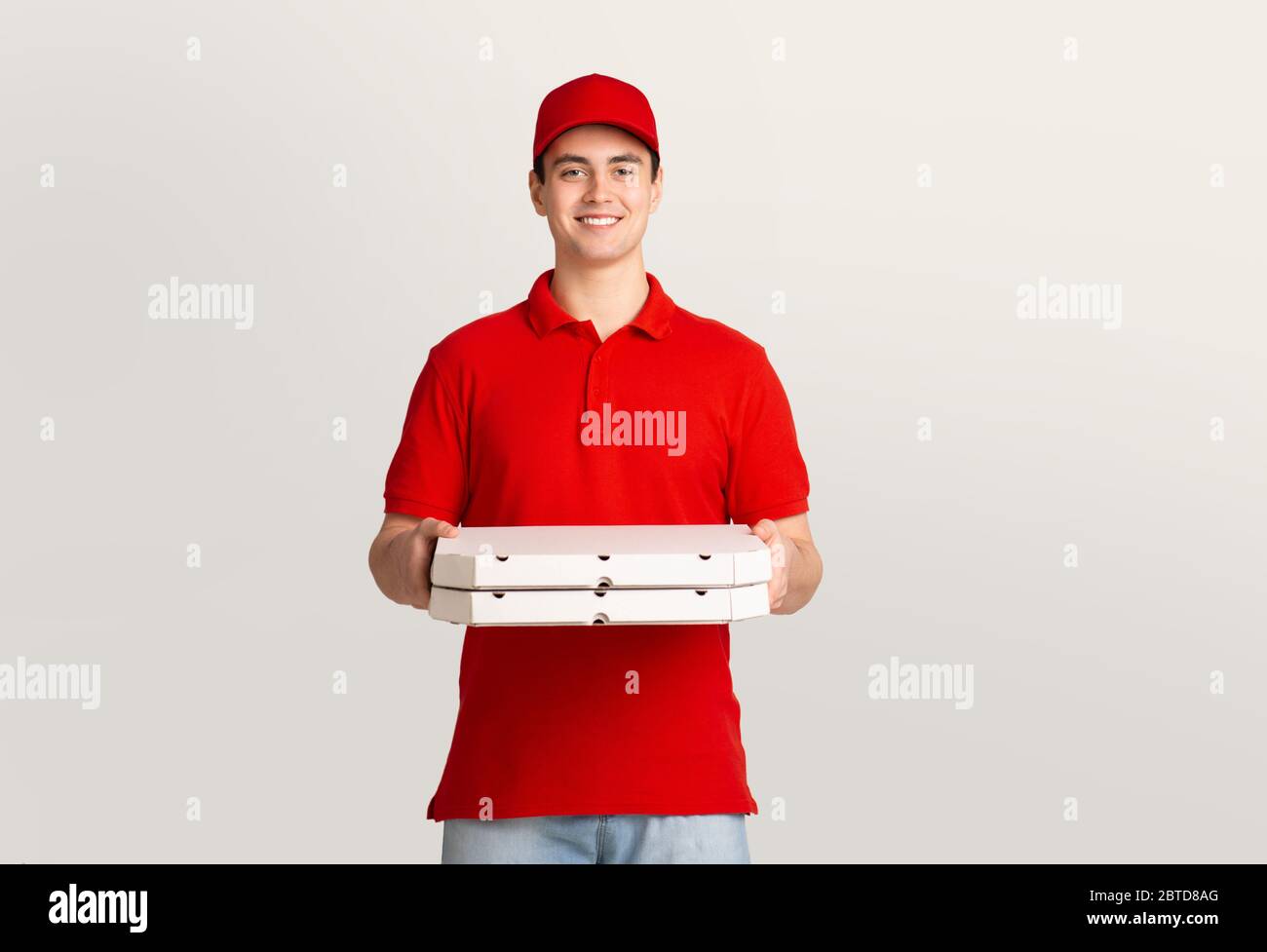 Food delivery. Smiling courier holds boxes with pizza Stock Photo - Alamy