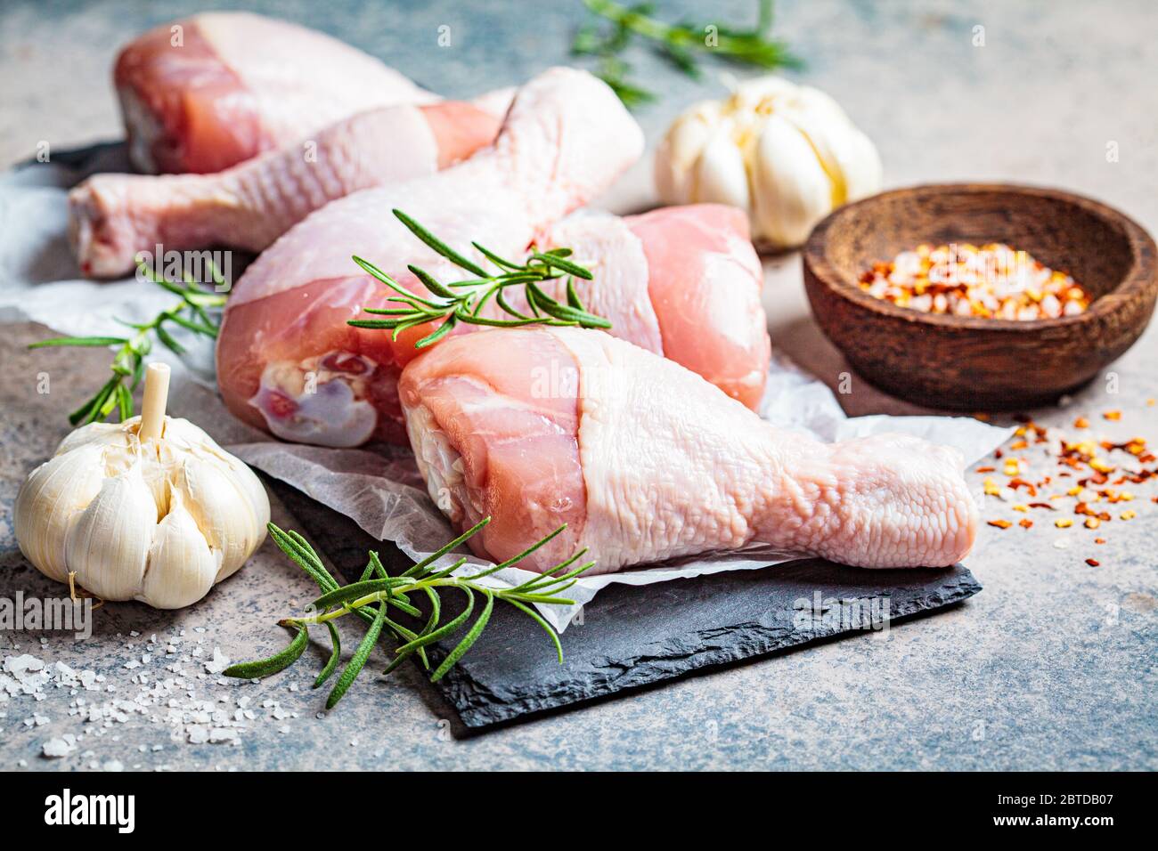 Raw chicken legs on a slate with spices, garlic and rosemary. Cooking ...
