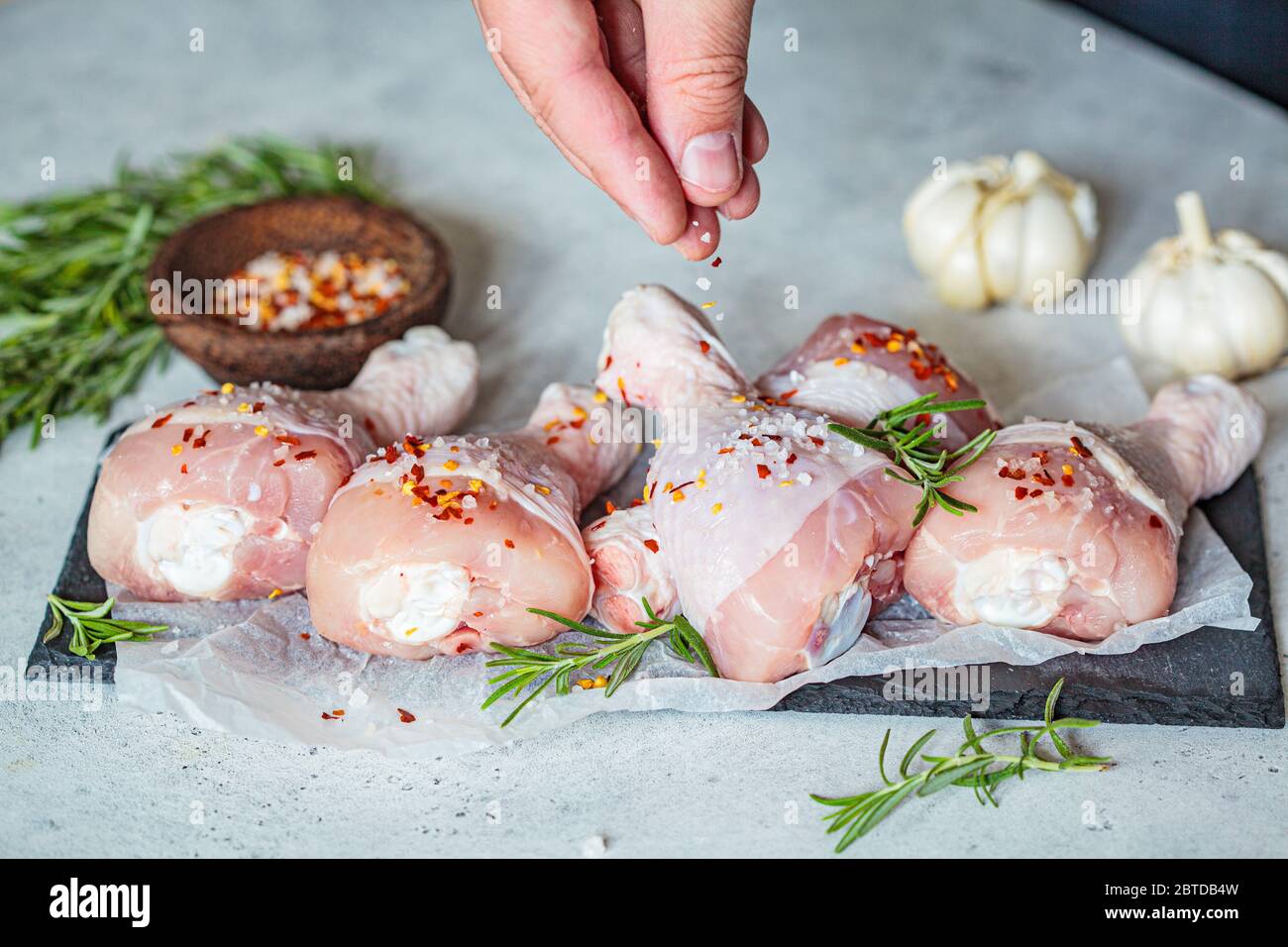 Raw chicken legs on a slate with spices, garlic and rosemary. Cooking ...
