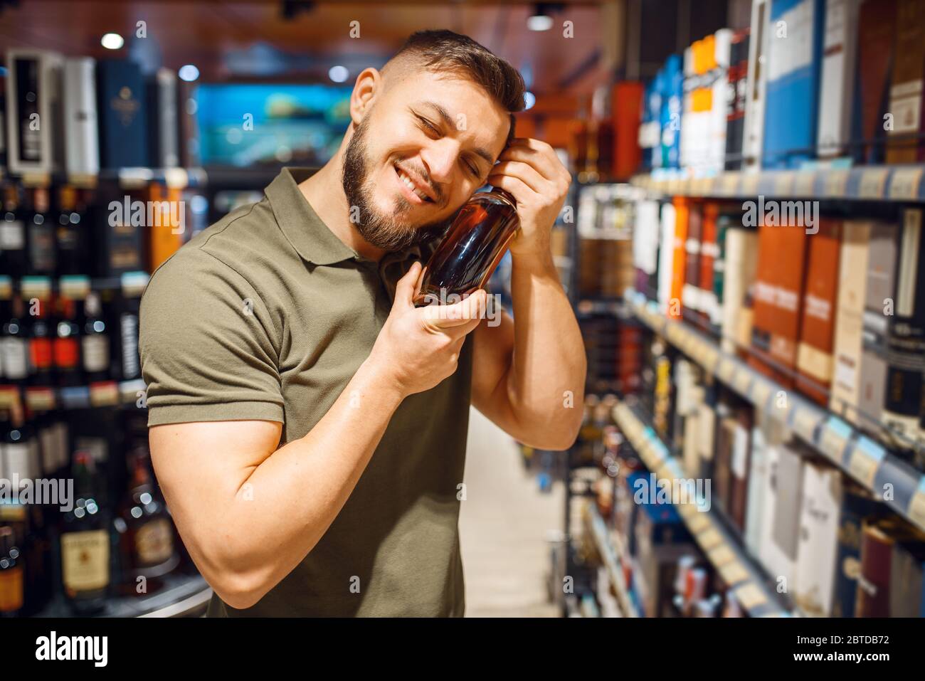 Man hugs bottle of alcohol in grocery store Stock Photo - Alamy