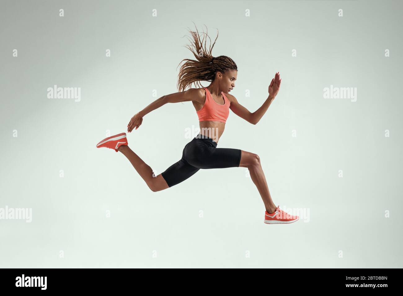 Never stop run. Full length of young african woman with perfect body in sports clothing jumping ...