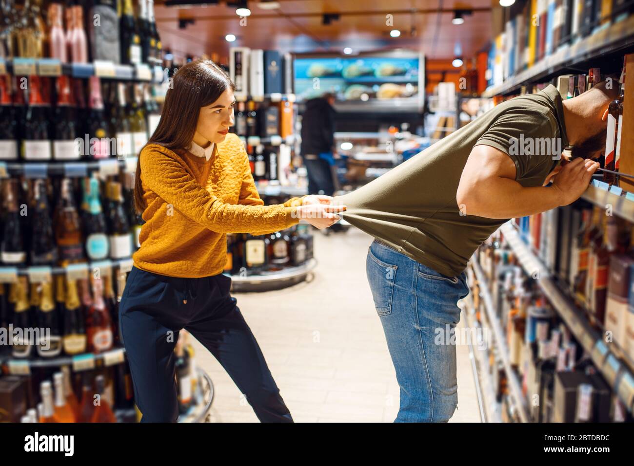 Funny couple choosing alcohol in grocery store Stock Photo - Alamy