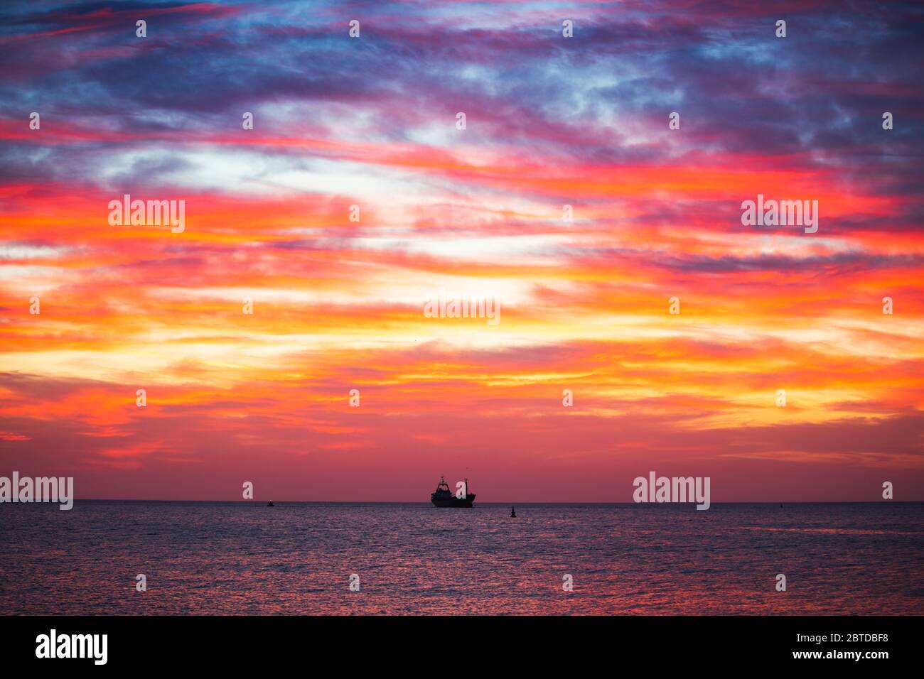 Sun setting at the sea with sailing cargo ship, scenic view Stock Photo ...