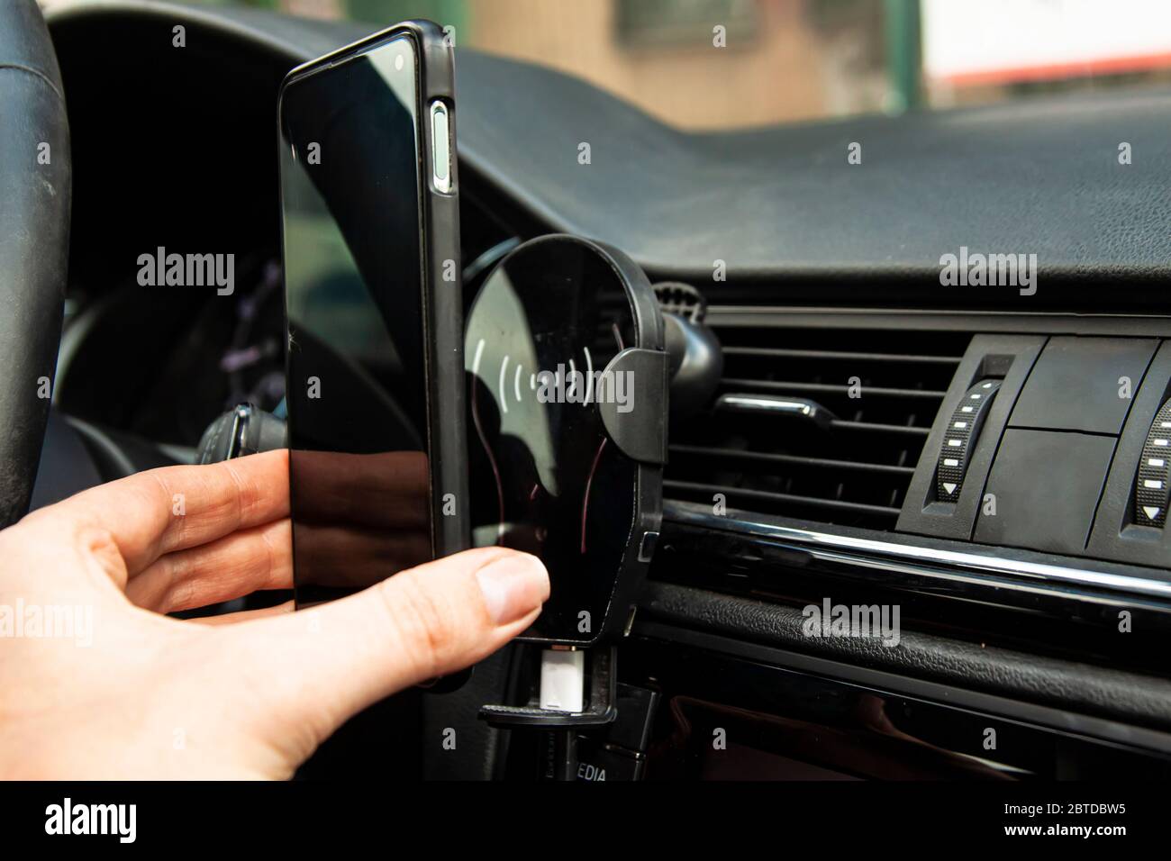 Female hand puts a modern phone on a wireless fast charge in the car ...