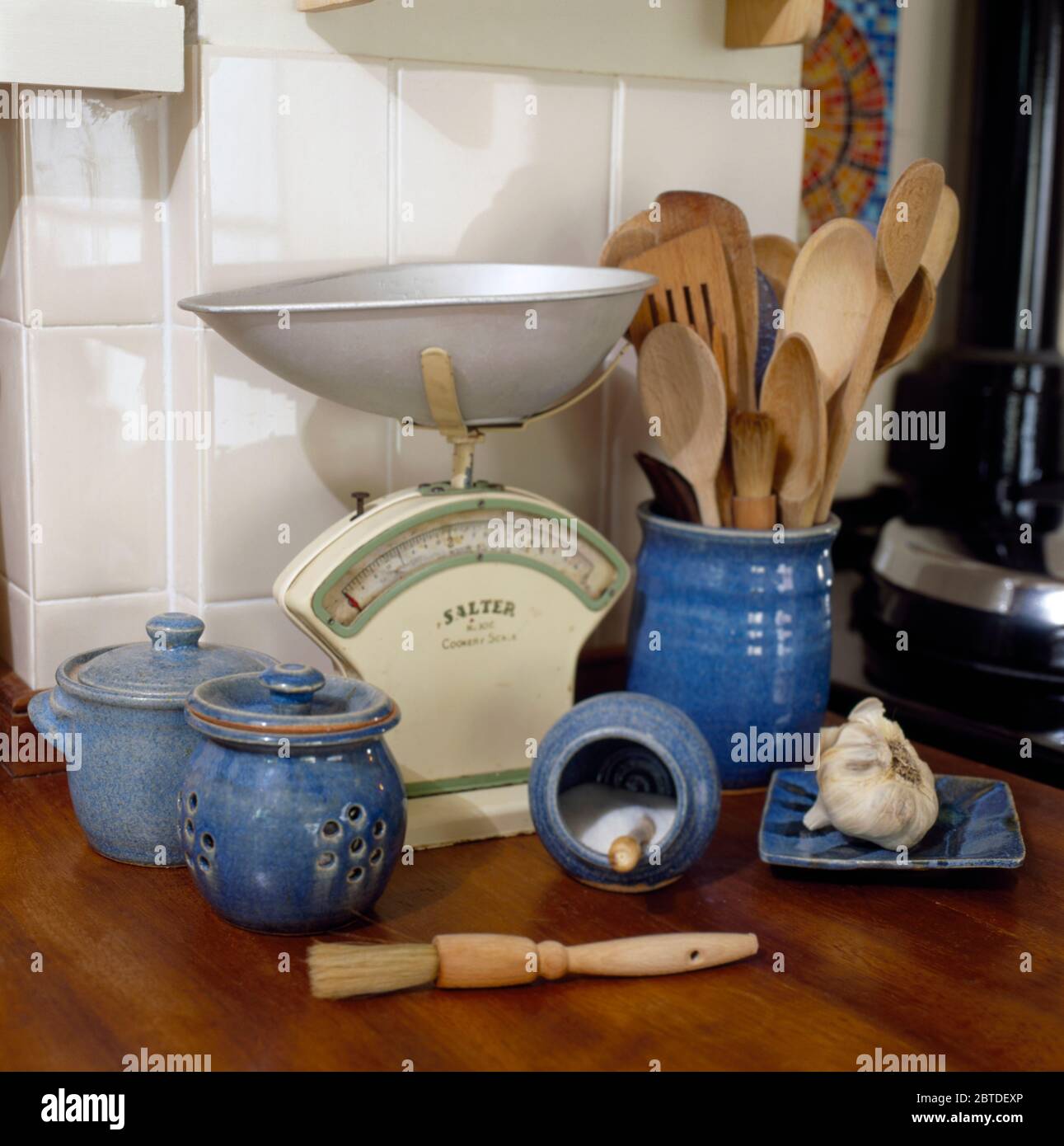 Blue pottery salt pots beside scales and jug of wooden utensils Stock ...