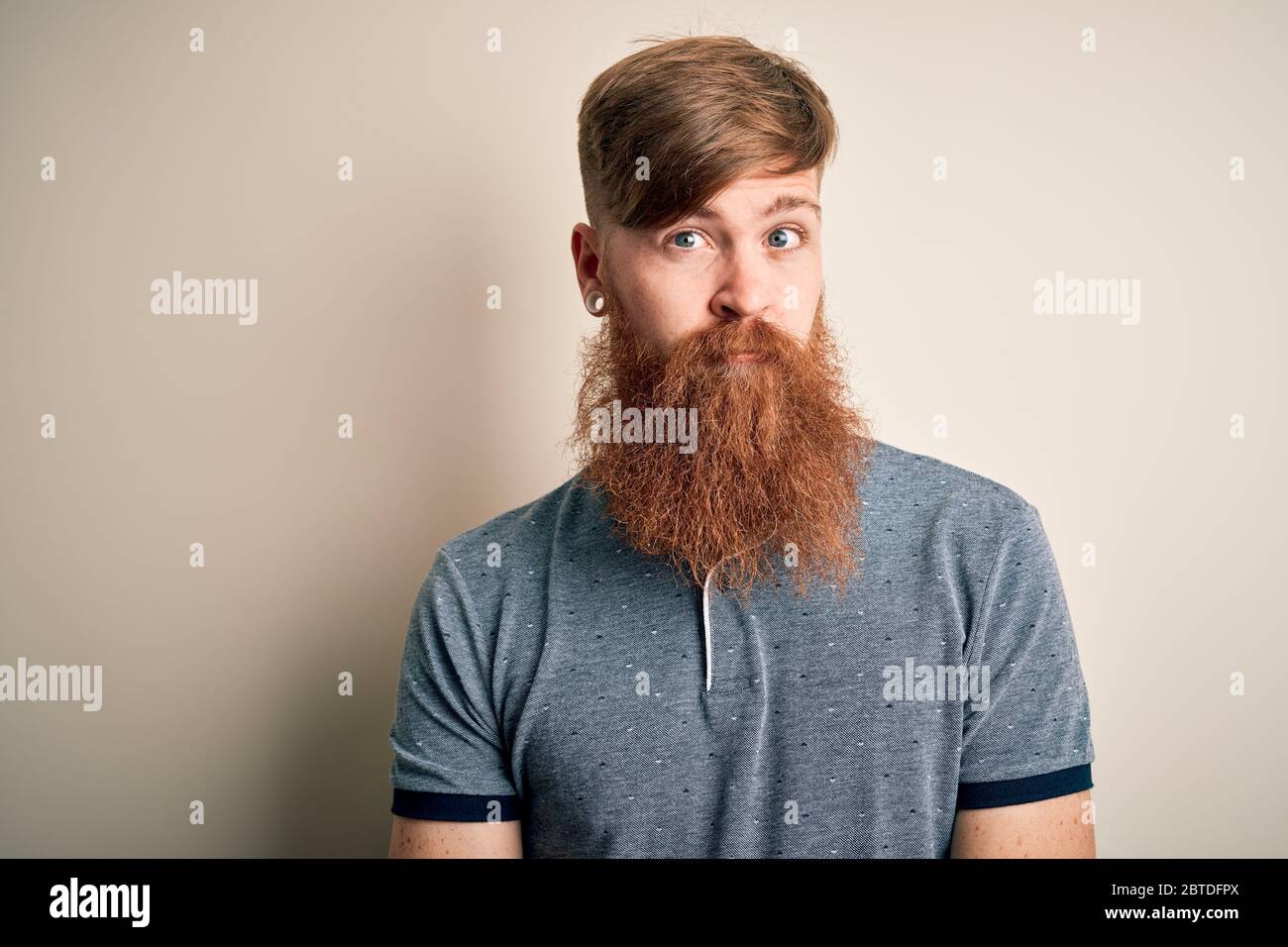 Handsome Irish redhead man with beard and arm tattoo standing over ...