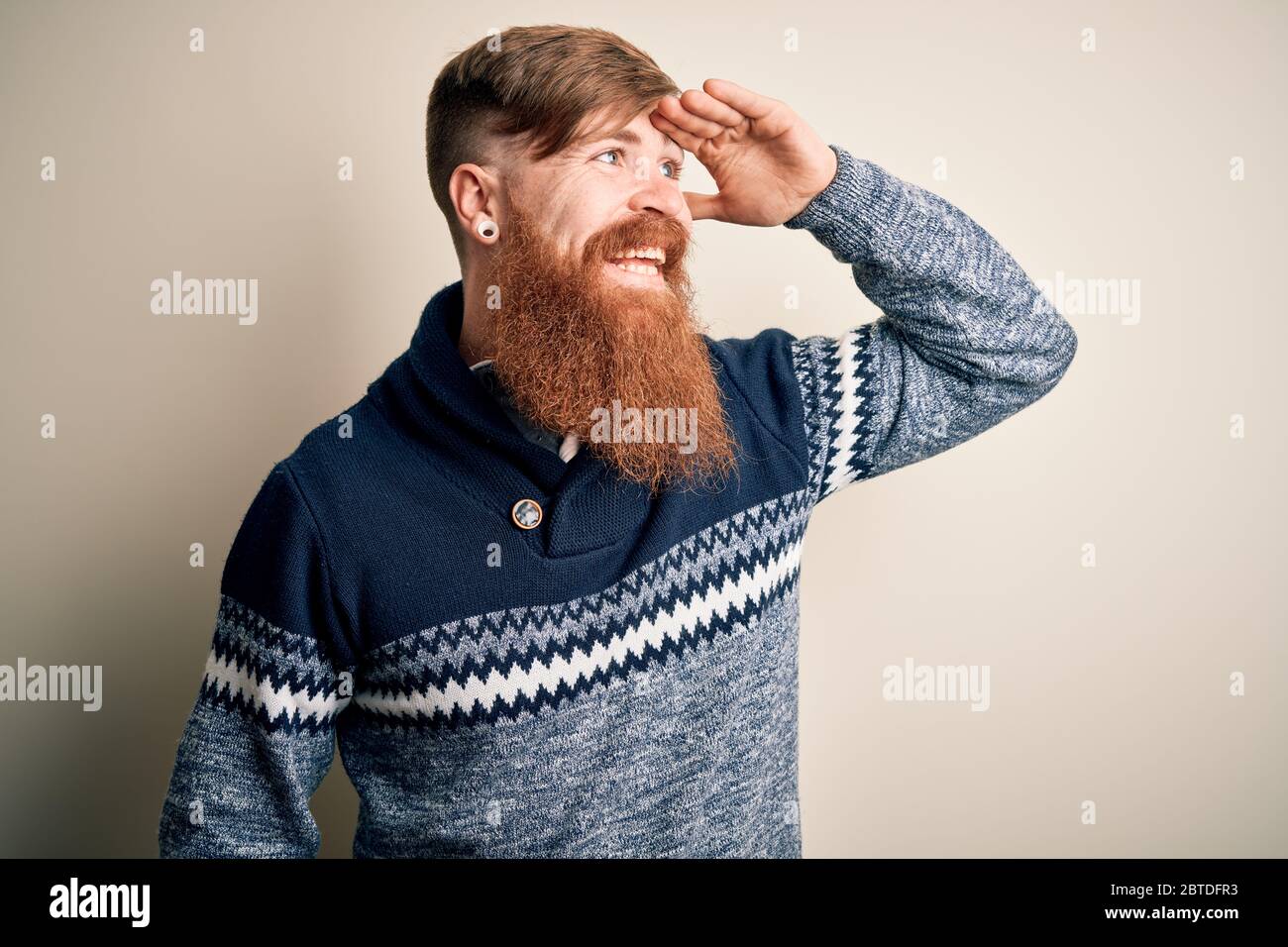 Handsome Irish redhead man with beard wearing winter sweater over ...