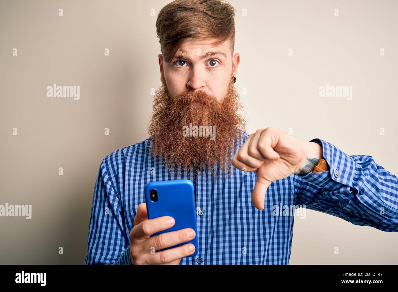 Redhead Irish man with beard using smartphone looking at screen over ...