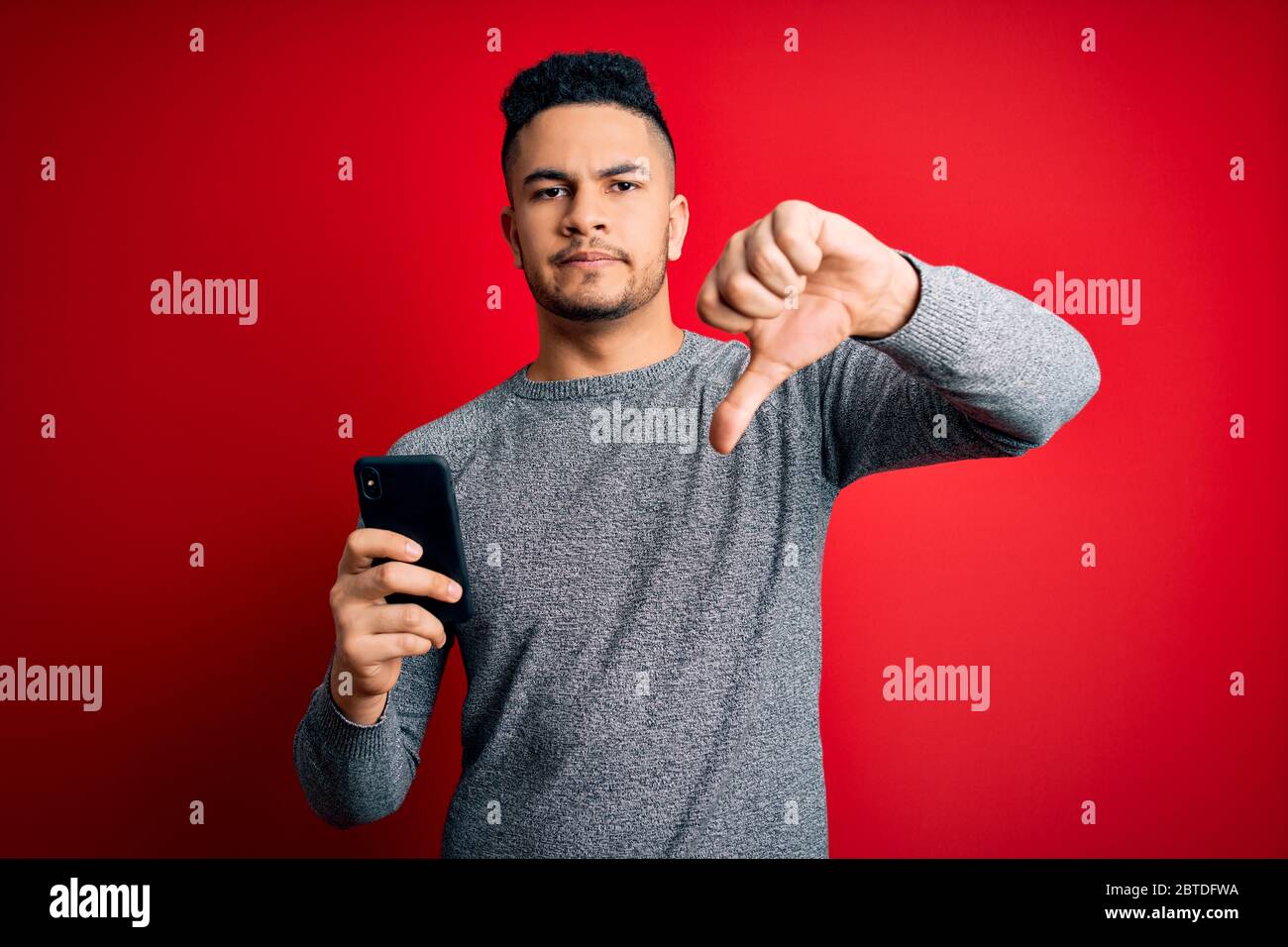 Young handsome man having conversation using smartphone over red ...