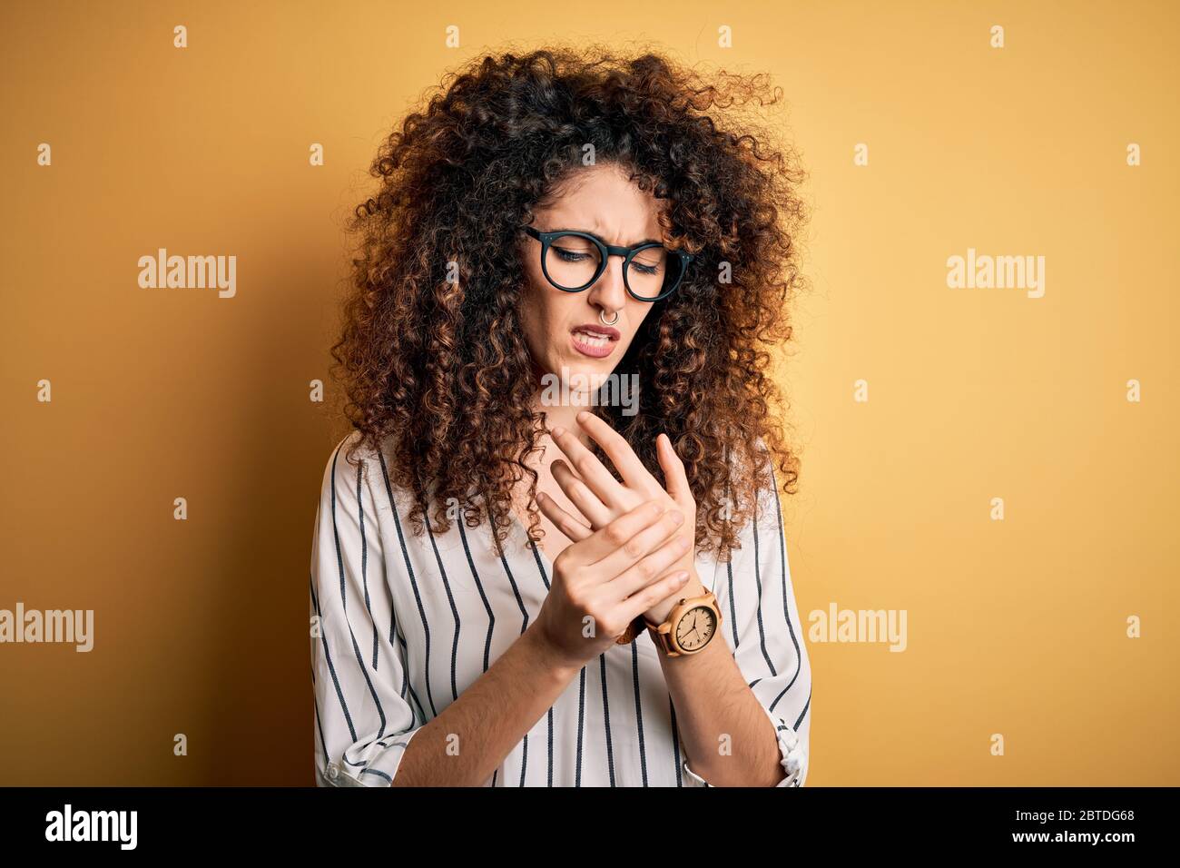 Young beautiful woman with curly hair and piercing wearing striped ...