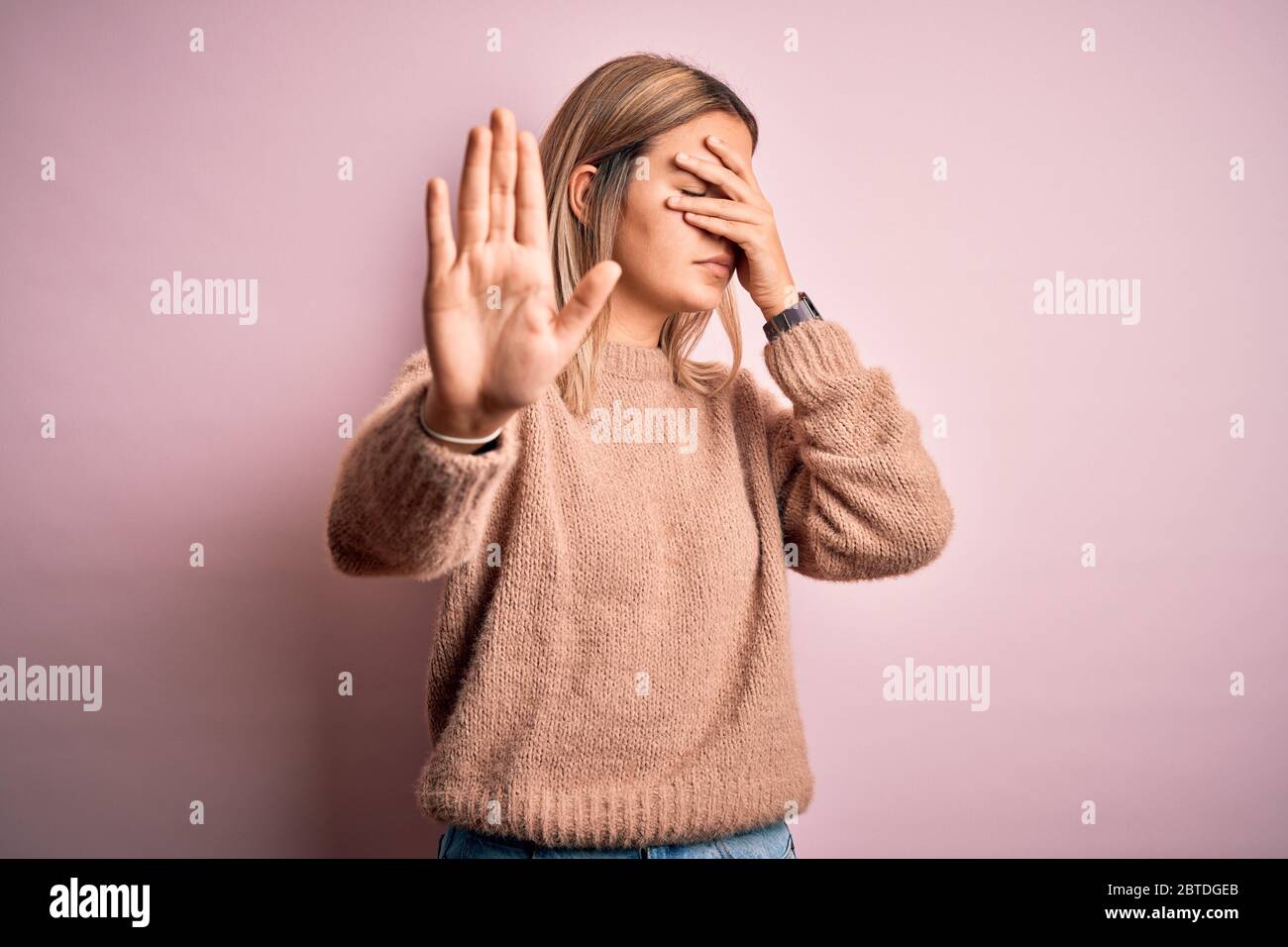 Young beautiful blonde woman wearing winter wool sweater over pink ...