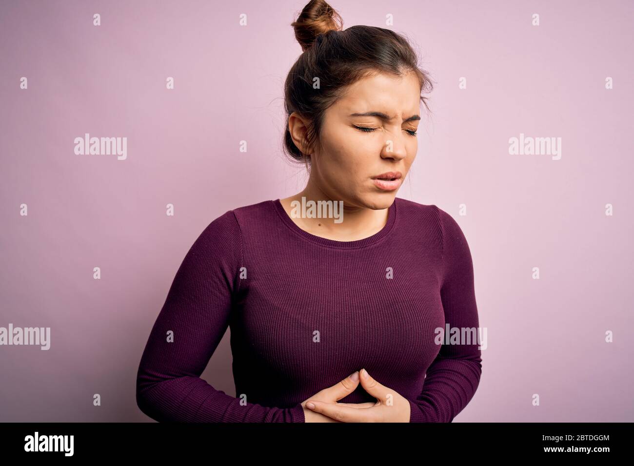 Beautiful young woman wearing casual bun hairstyle over pink isolated ...