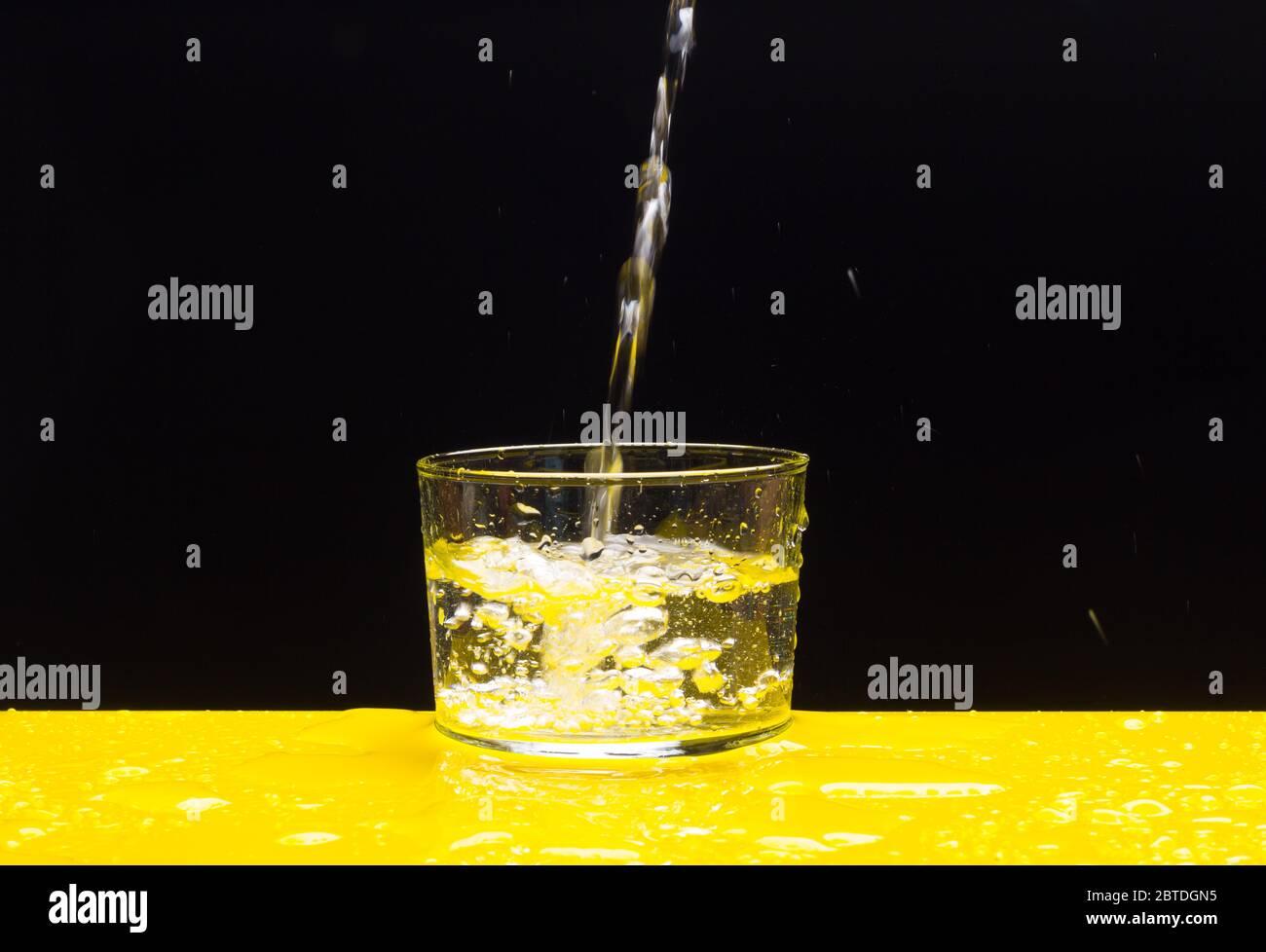 Splash and splash of water in a glass that is filling with fresh, clear ...