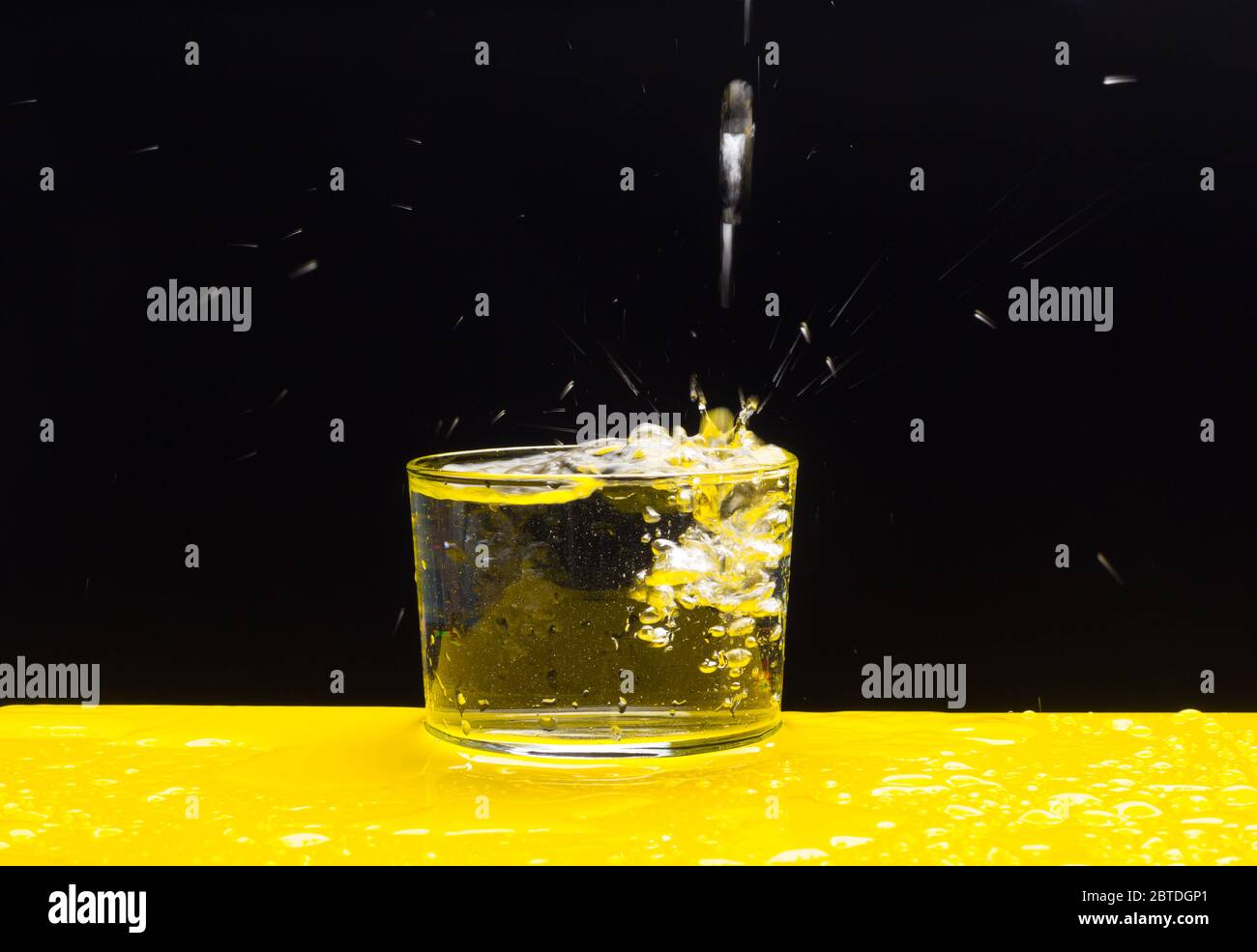 Splash and splash of water in a glass that is filling with fresh, clear ...