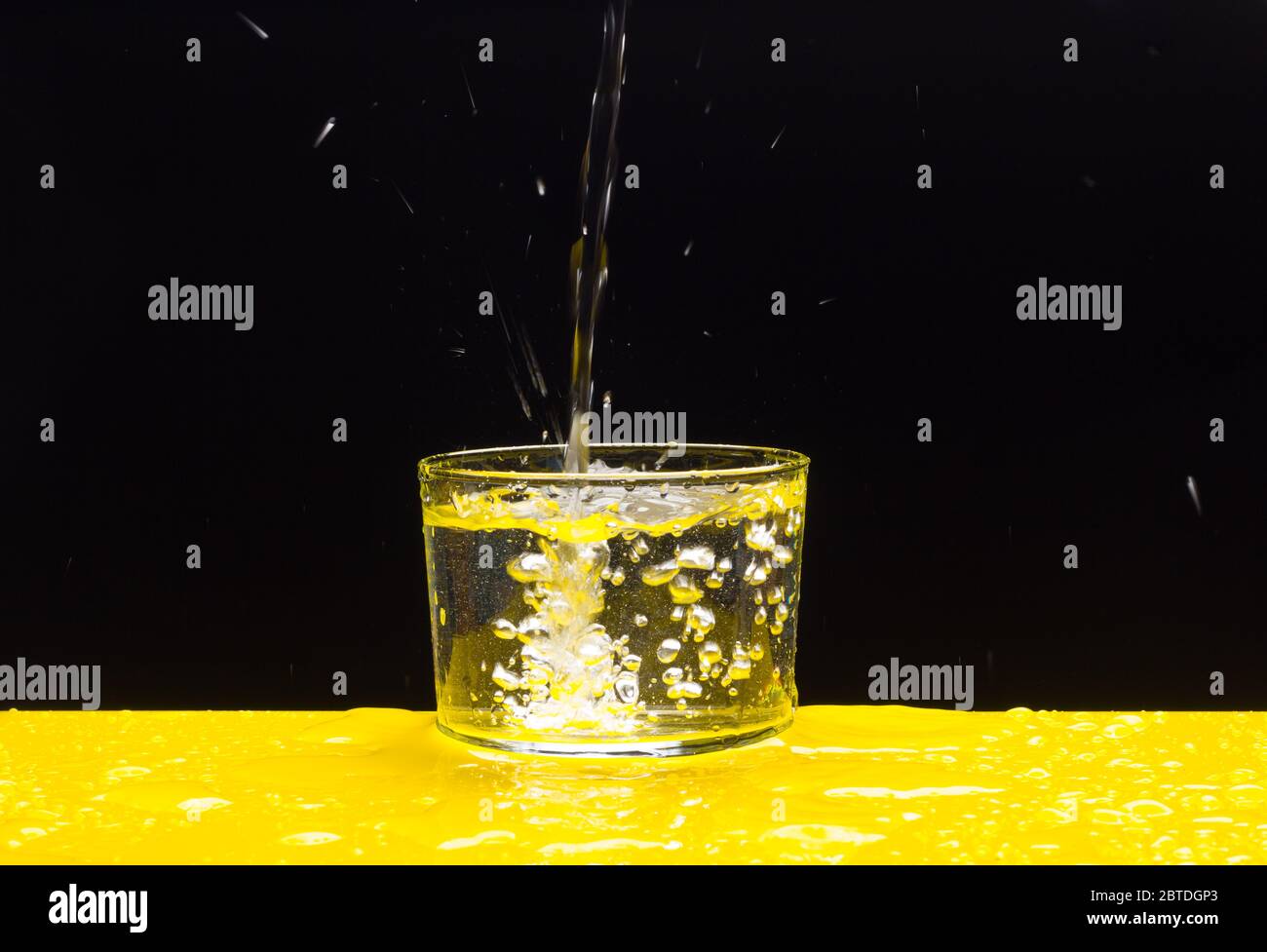 Splash and splash of water in a glass that is filling with fresh, clear ...