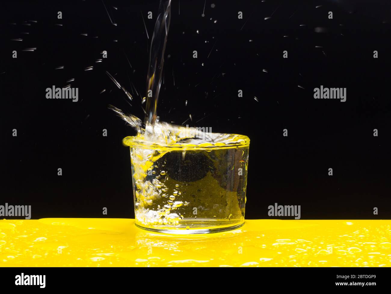 Splash and splash of water in a glass that is filling with fresh, clear ...