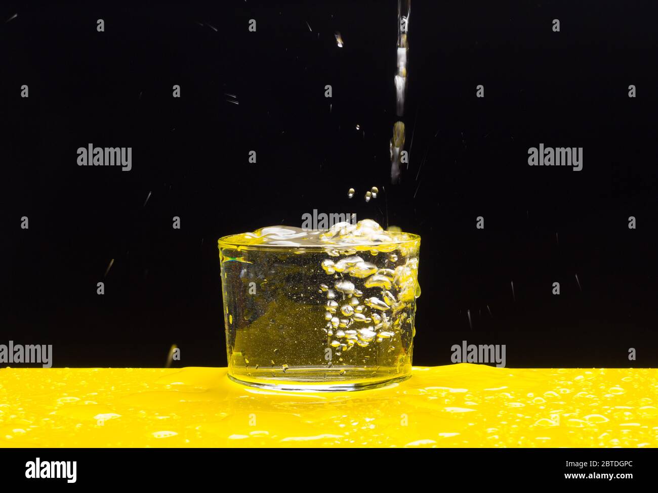 Splash and splash of water in a glass that is filling with fresh, clear ...