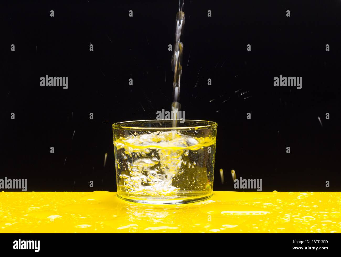 Splash and splash of water in a glass that is filling with fresh, clear ...