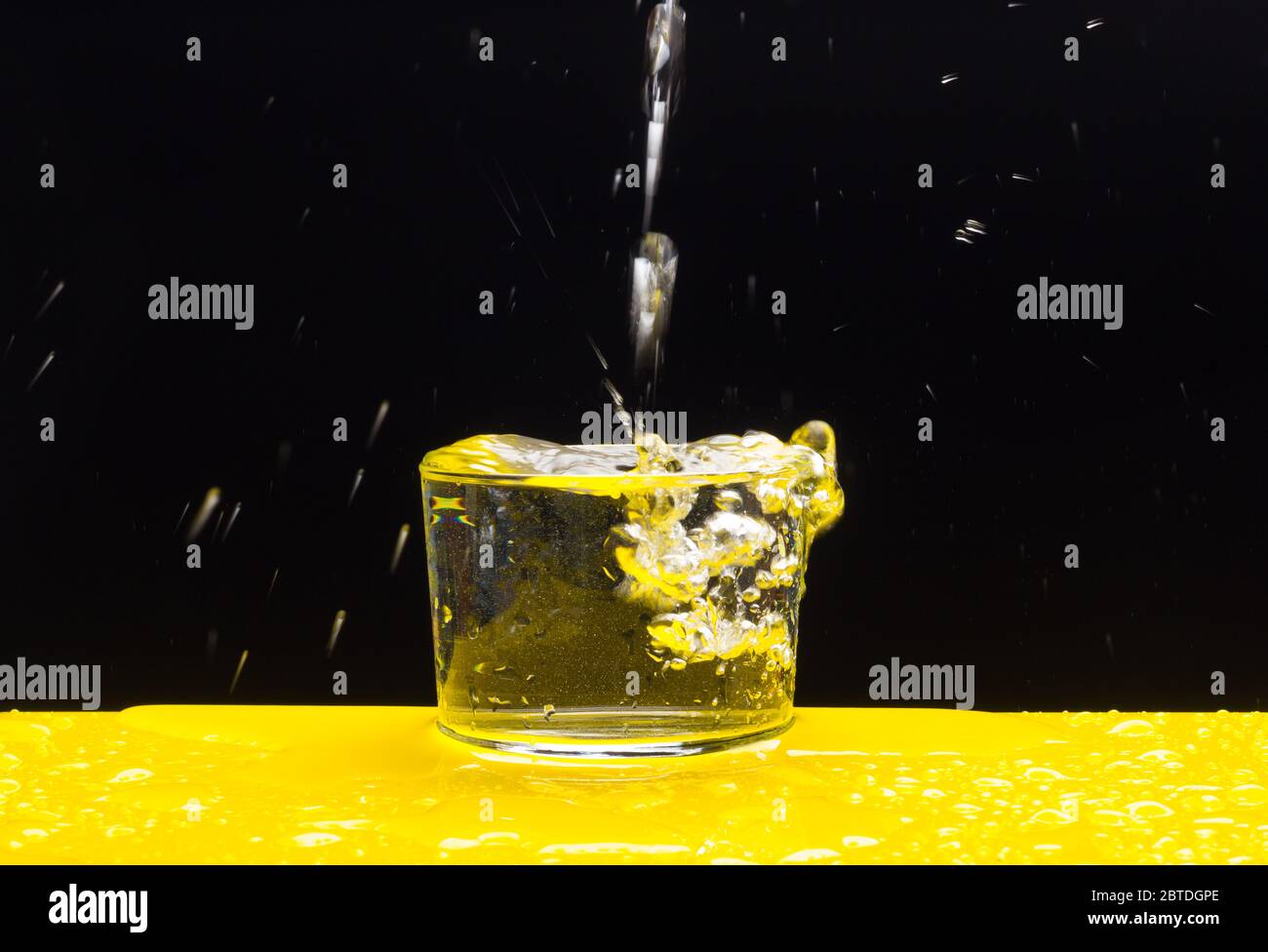 Splash and splash of water in a glass that is filling with fresh, clear ...