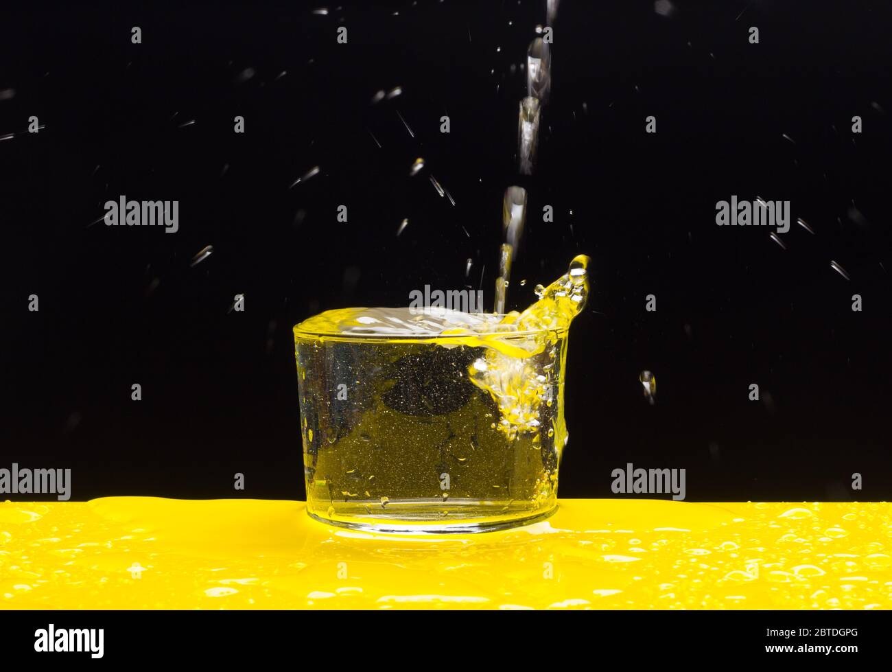 Splash and splash of water in a glass that is filling with fresh, clear ...