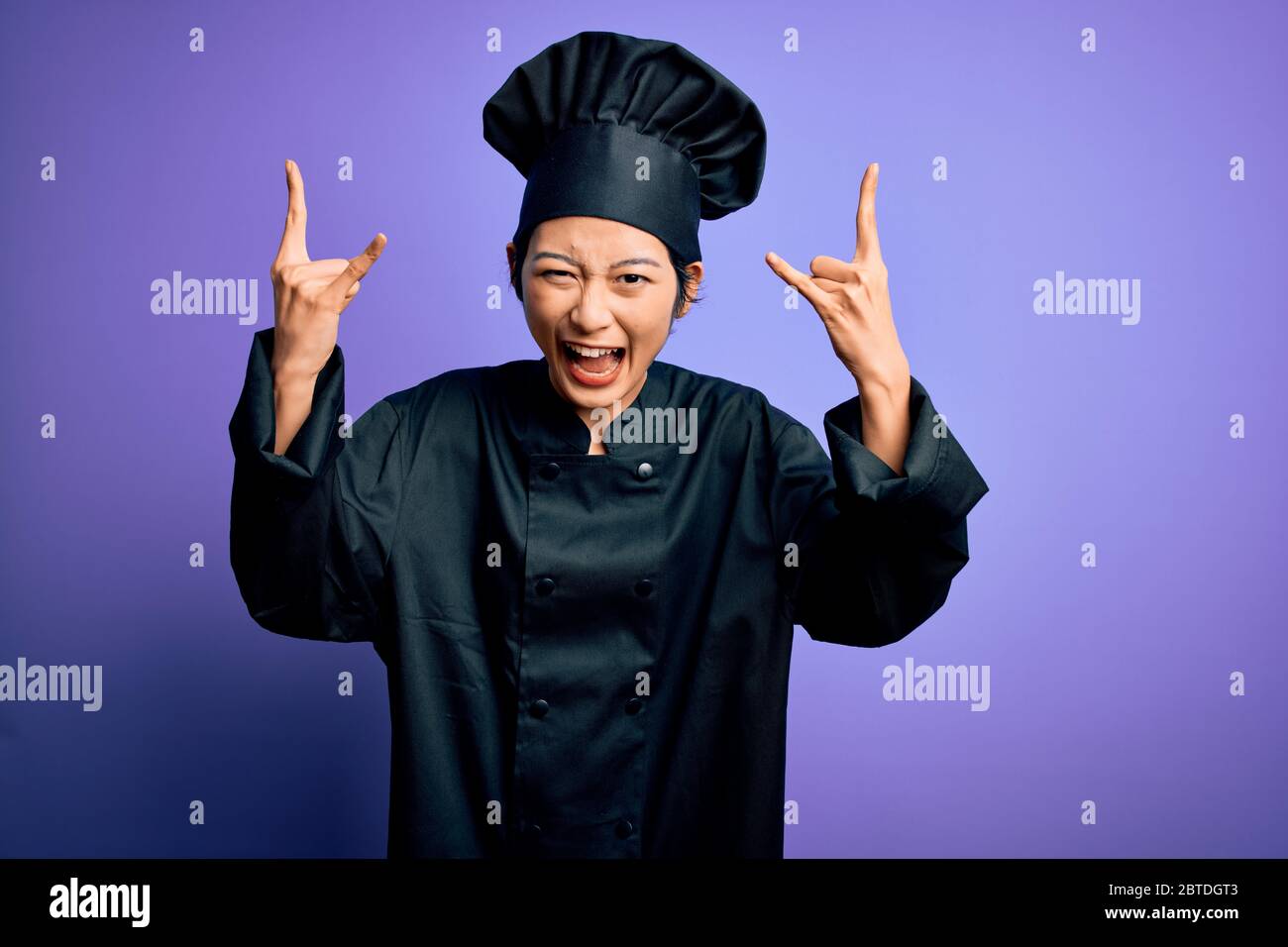 Young beautiful chinese chef woman wearing cooker uniform and hat over ...