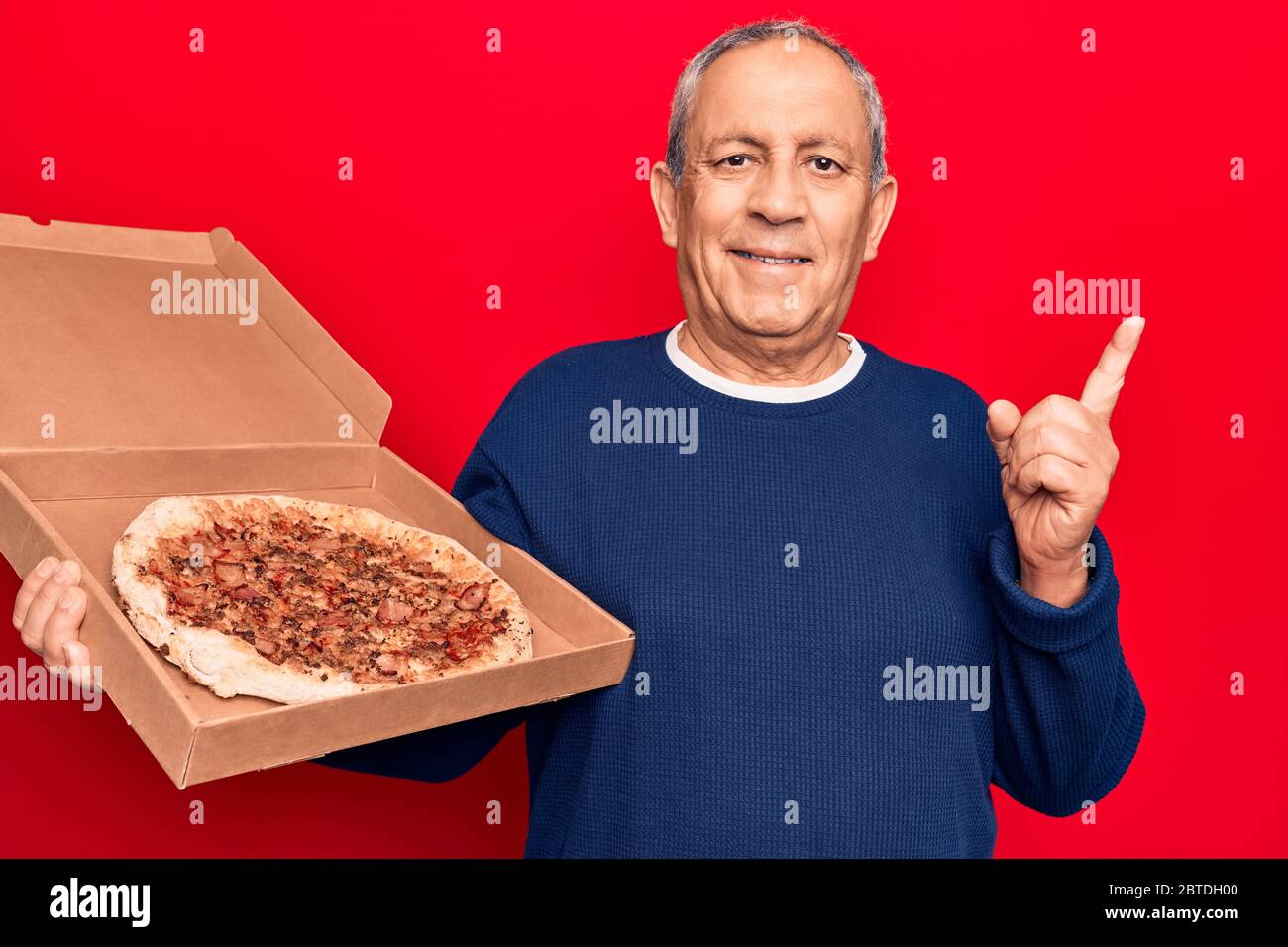 Senior man with grey hair holding delivery cardboard of italian pizza ...