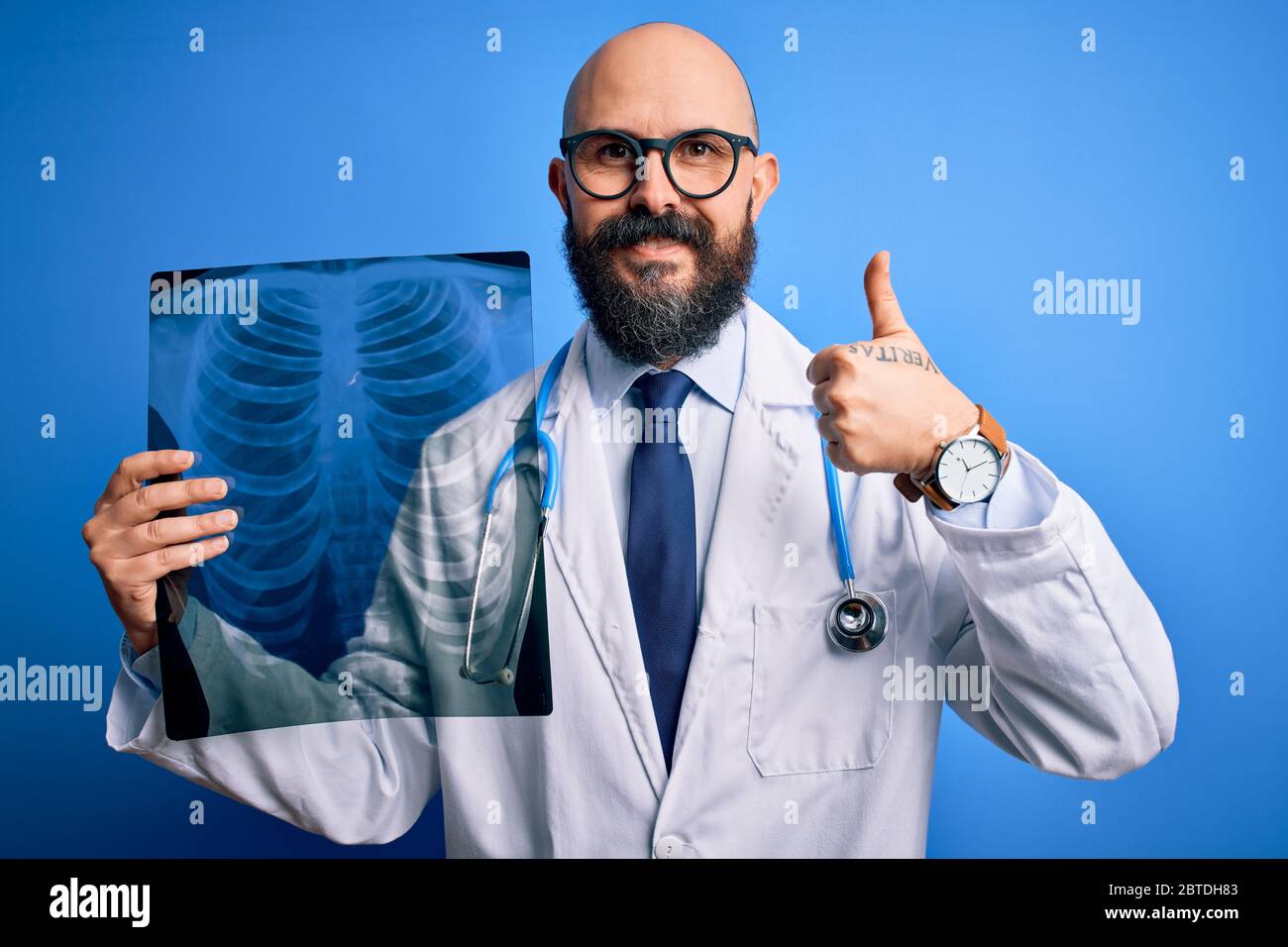 Handsome bald doctor man with beard wearing stethoscope holding chest ...