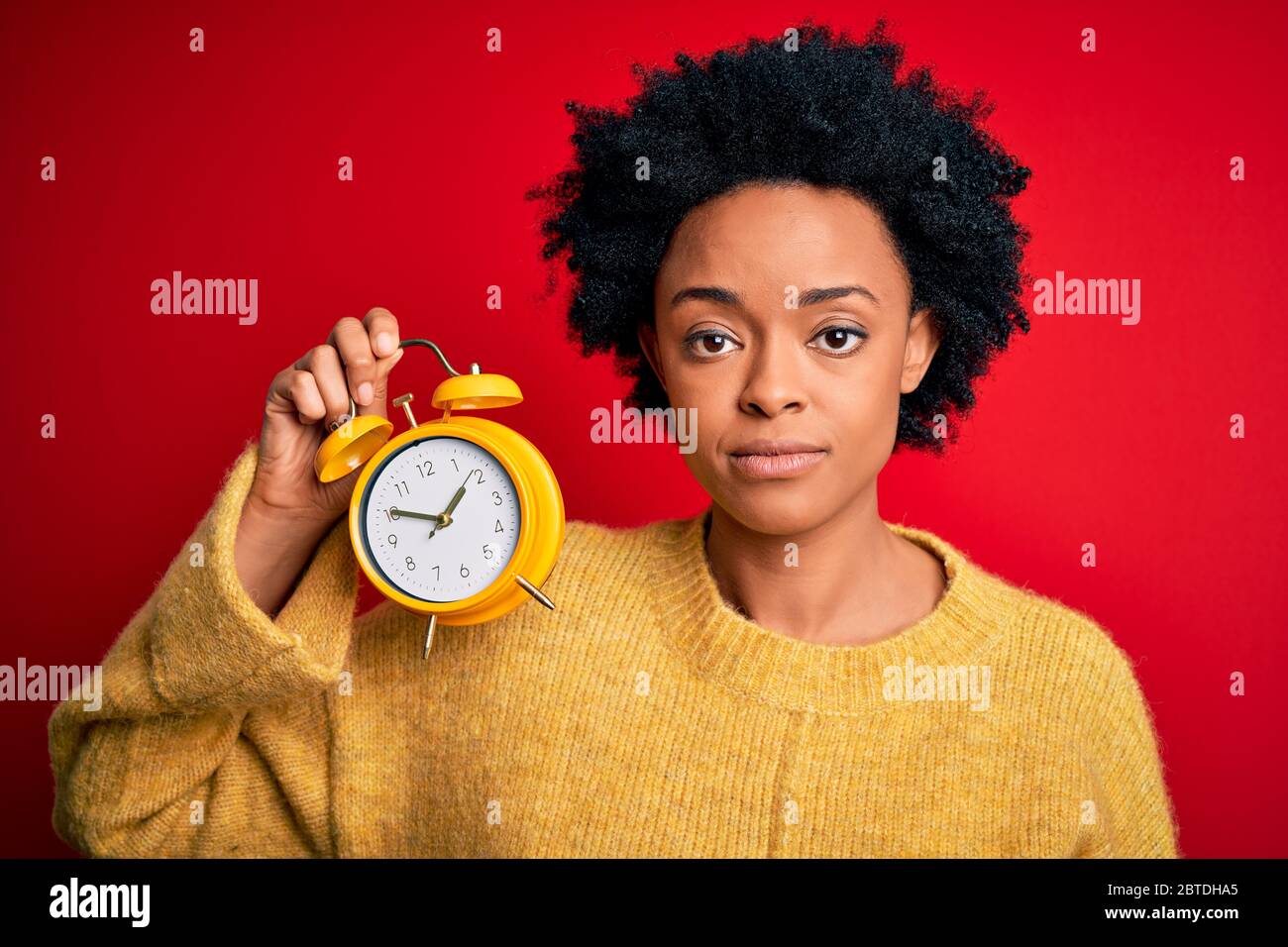 Young African American afro woman with curly hair holding vintage alarm ...