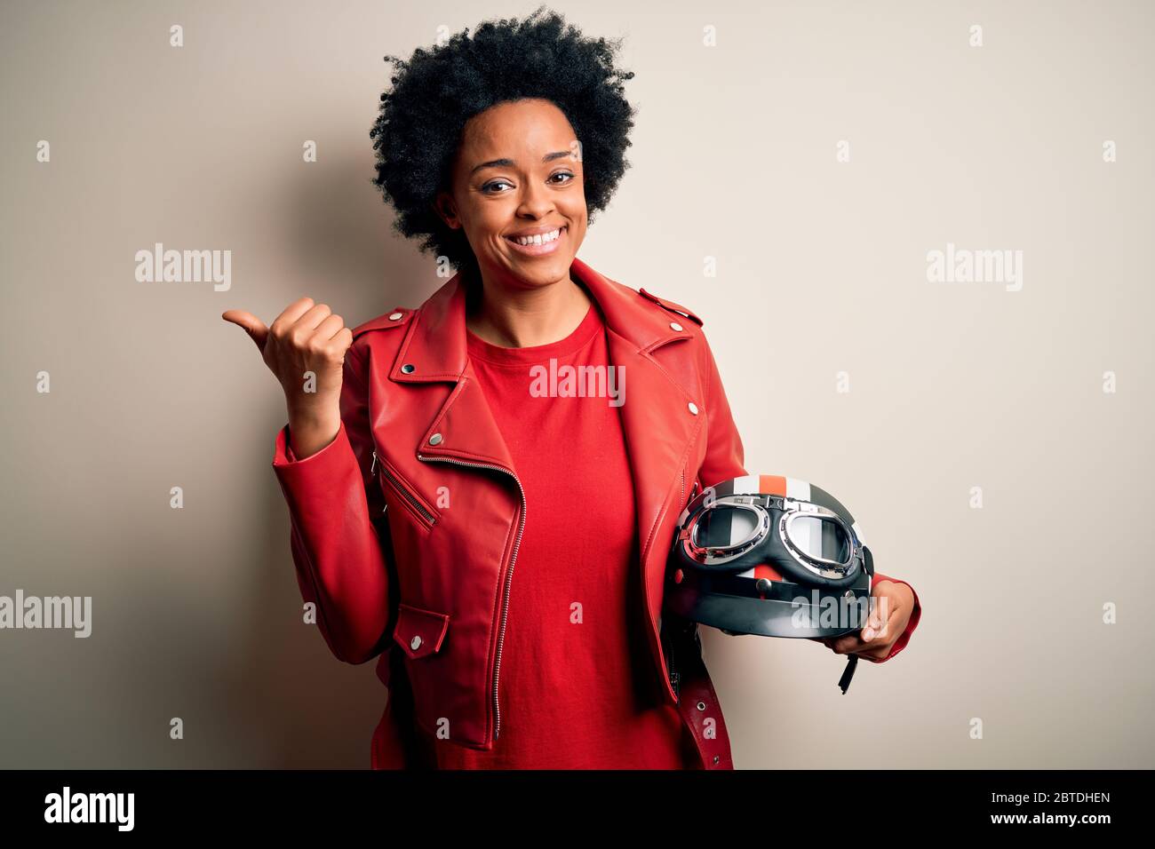 Young African American afro motorcyclist woman with curly hair holding ...