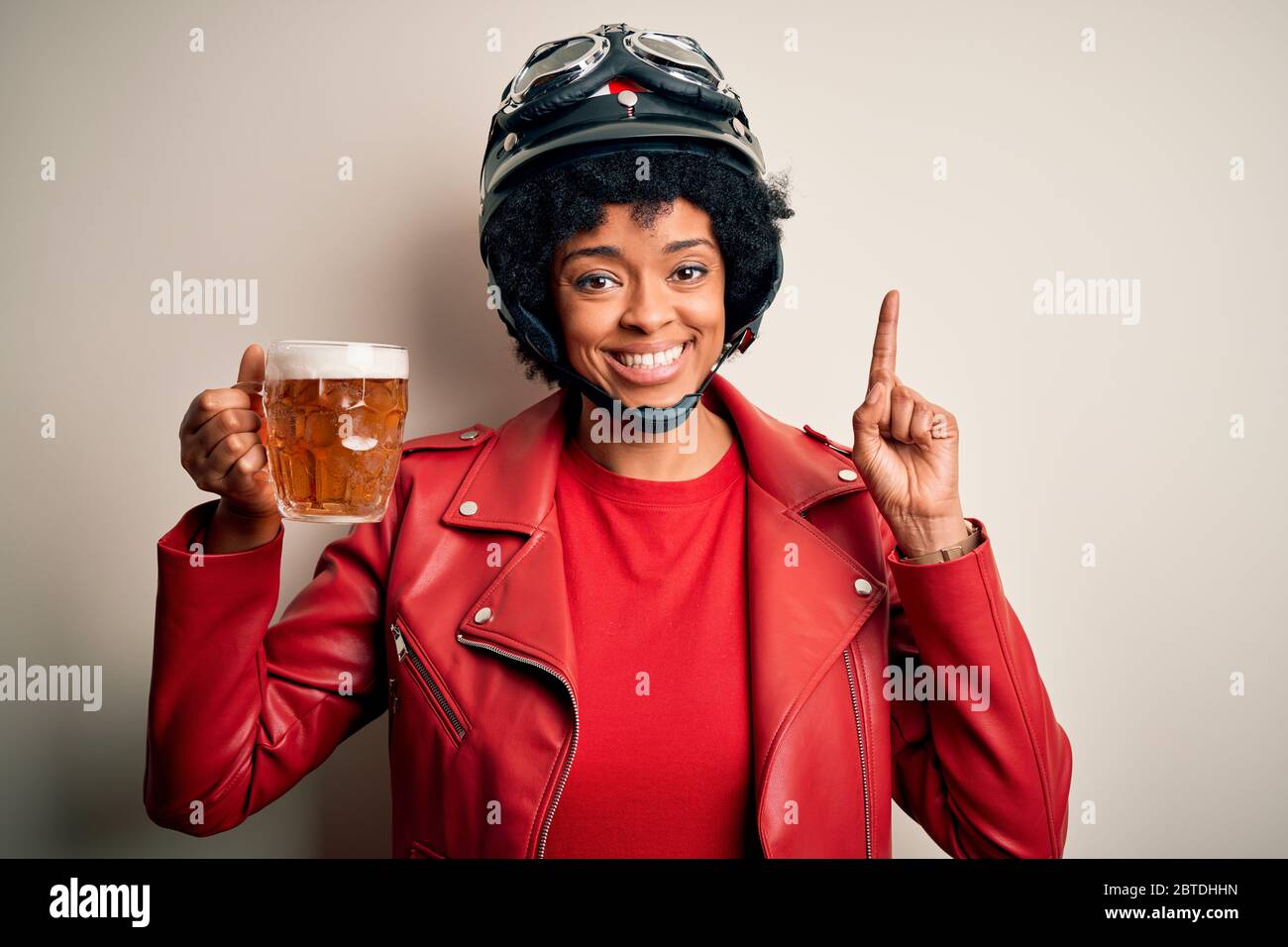 Young African American afro motorcyclist woman with curly hair drinking ...