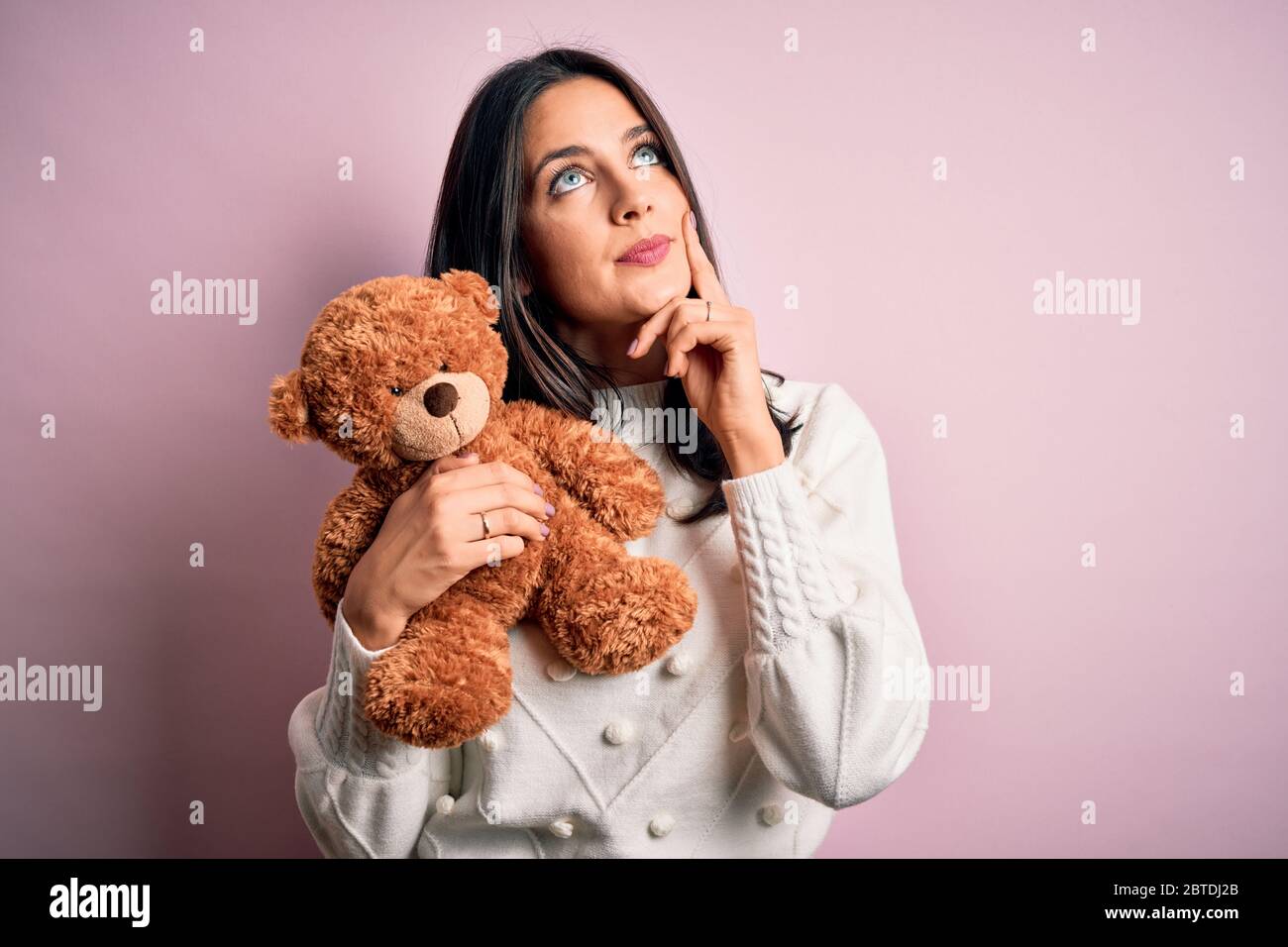 Young brunette woman with blue eyes hugging teddy bear stuffed animal ...