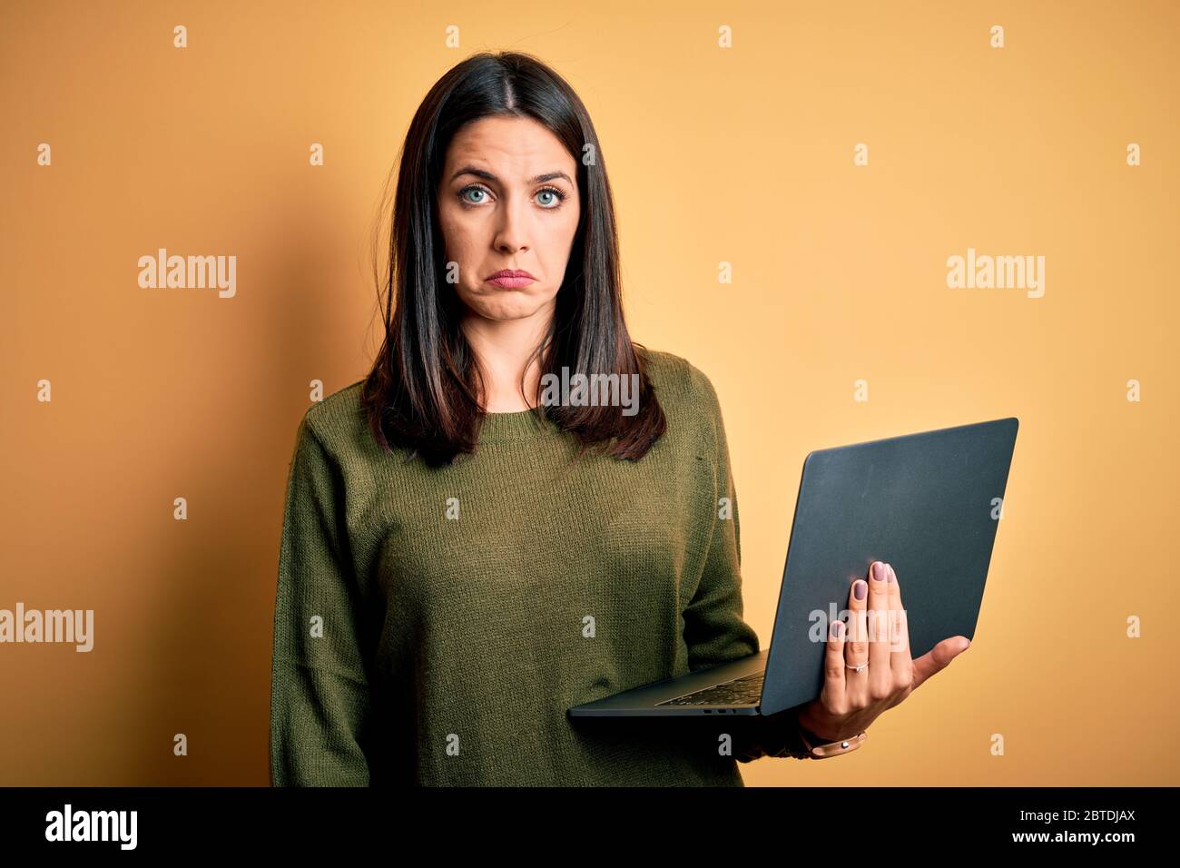 Young brunette woman with blue eyes working using computer laptop over ...