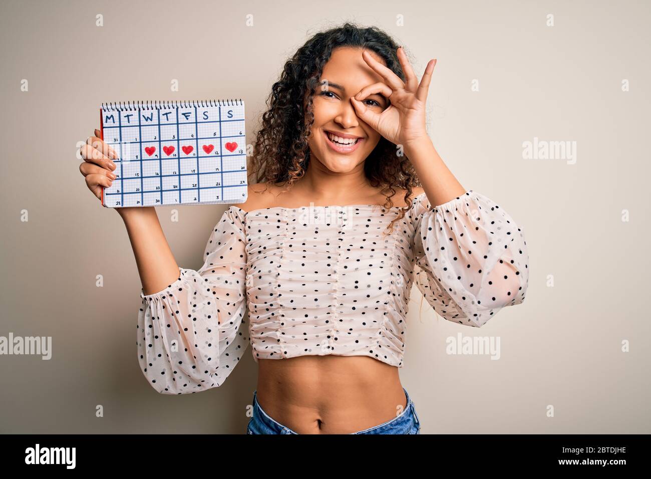Young beautiful woman with curly hair holding mensturation calendar ...