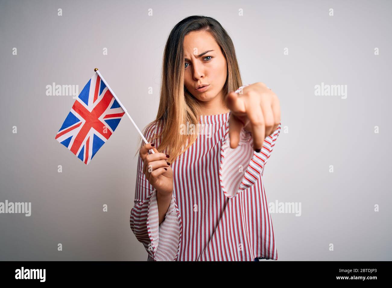 Young beautiful blonde woman with blue eyes holding united kingdom flag ...
