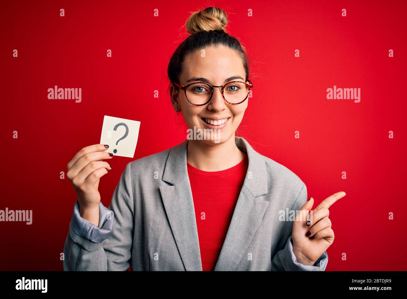 Young beautiful blonde woman with blue eyes holding reminder paper with ...
