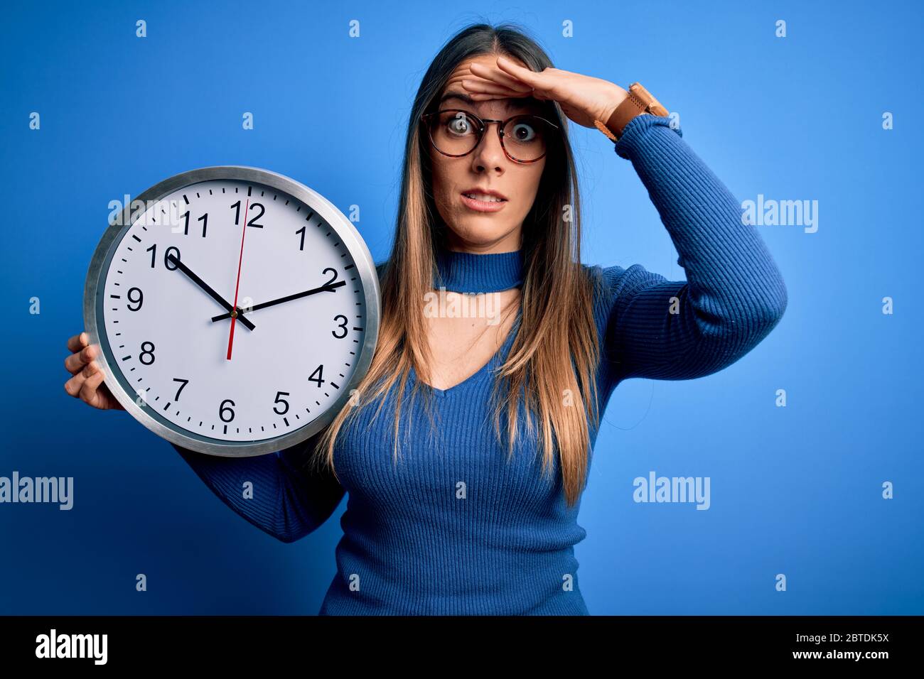 Young blonde woman with blue eyes holding big minute clock over ...