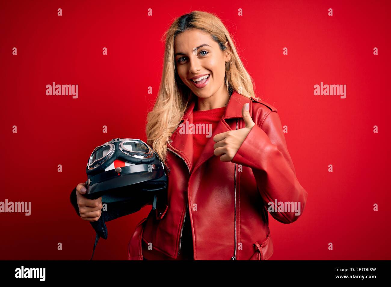 Young beautiful blonde motorcyclist woman holding moto helmet over ...
