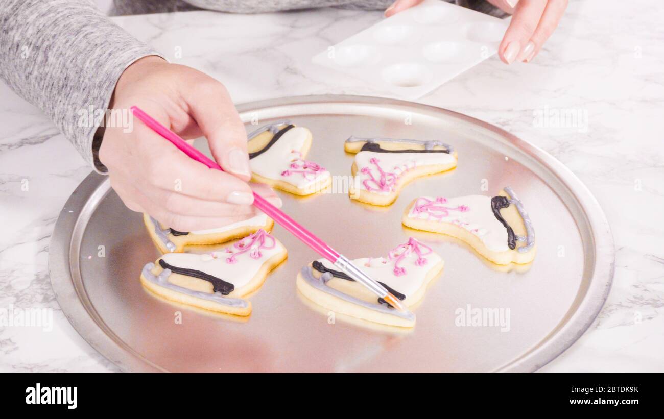 Brushing edible glitter on iced figure skate sugar cookies Stock Photo ...