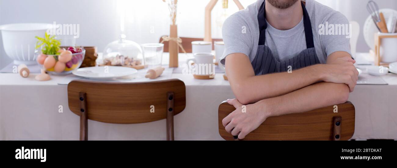 Happy young man wearing apron preparing to cook in kitchen at home ...