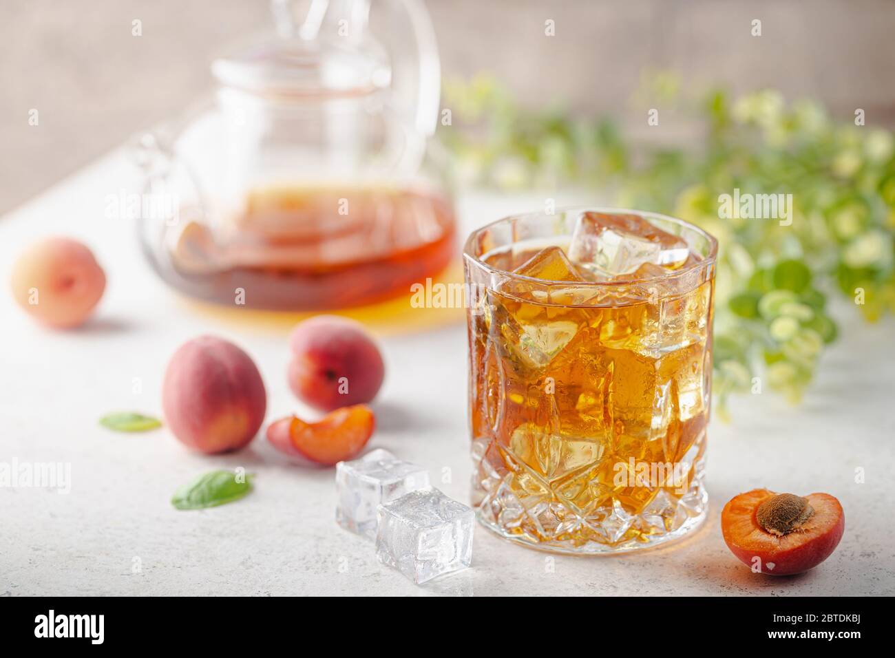 Glass of peach or apricot iced tea with fruit slices against white ...