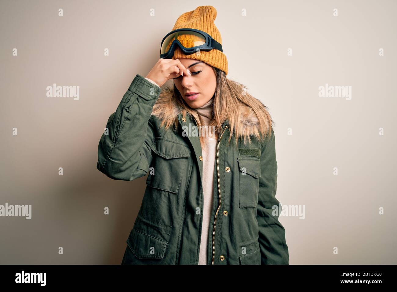 Young brunette skier woman wearing snow clothes and ski goggles over ...