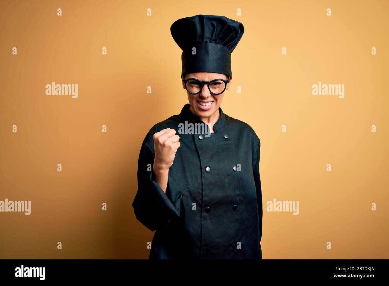 Young beautiful brunette chef woman wearing cooker uniform and hat over ...