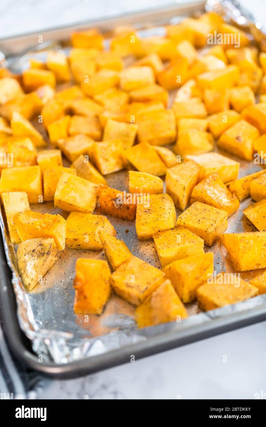 Roasting butternut squash with salt and pepper in olive oil Stock Photo ...