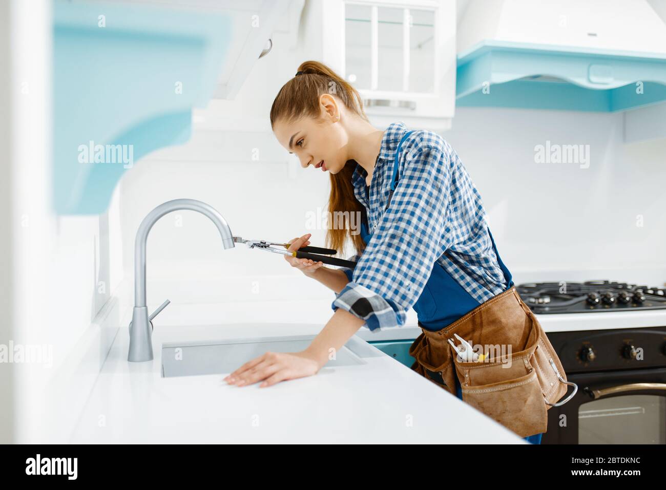 Cute female plumber in uniform fixing faucet Stock Photo - Alamy